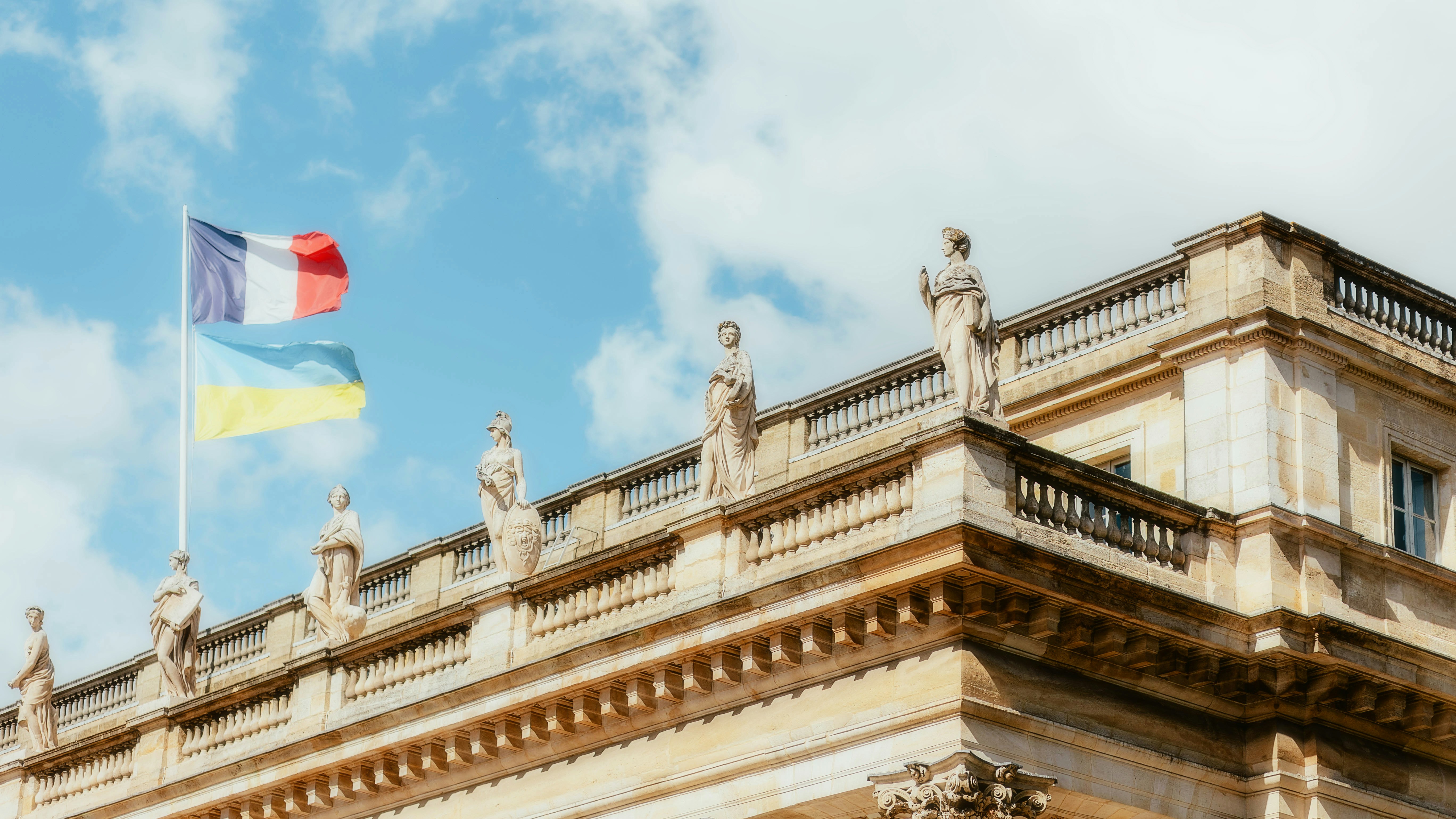 Flag atop a Parisian façade: statues guard the corner
