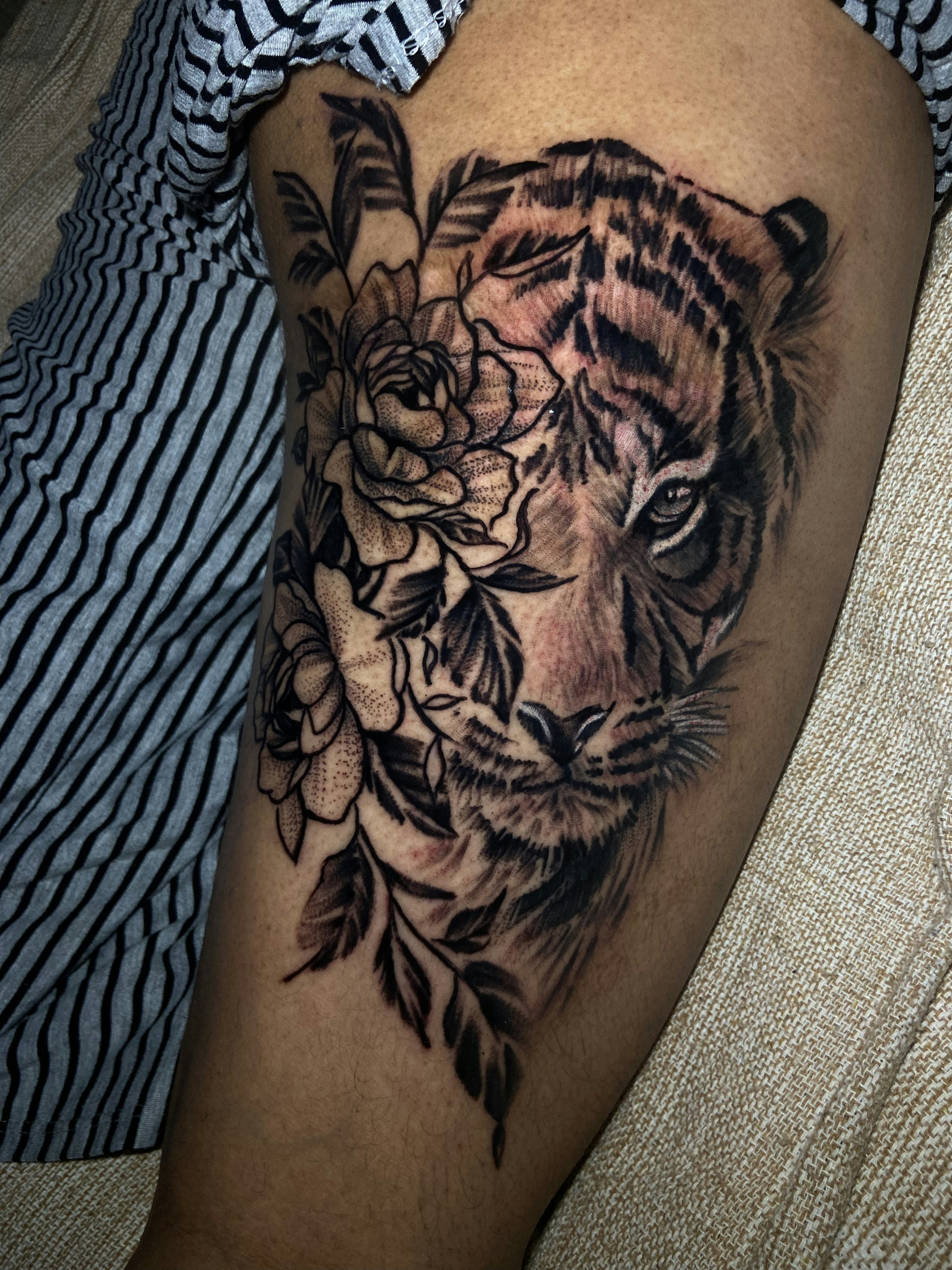 a tattoo of a tiger and flowers on a woman's thigh