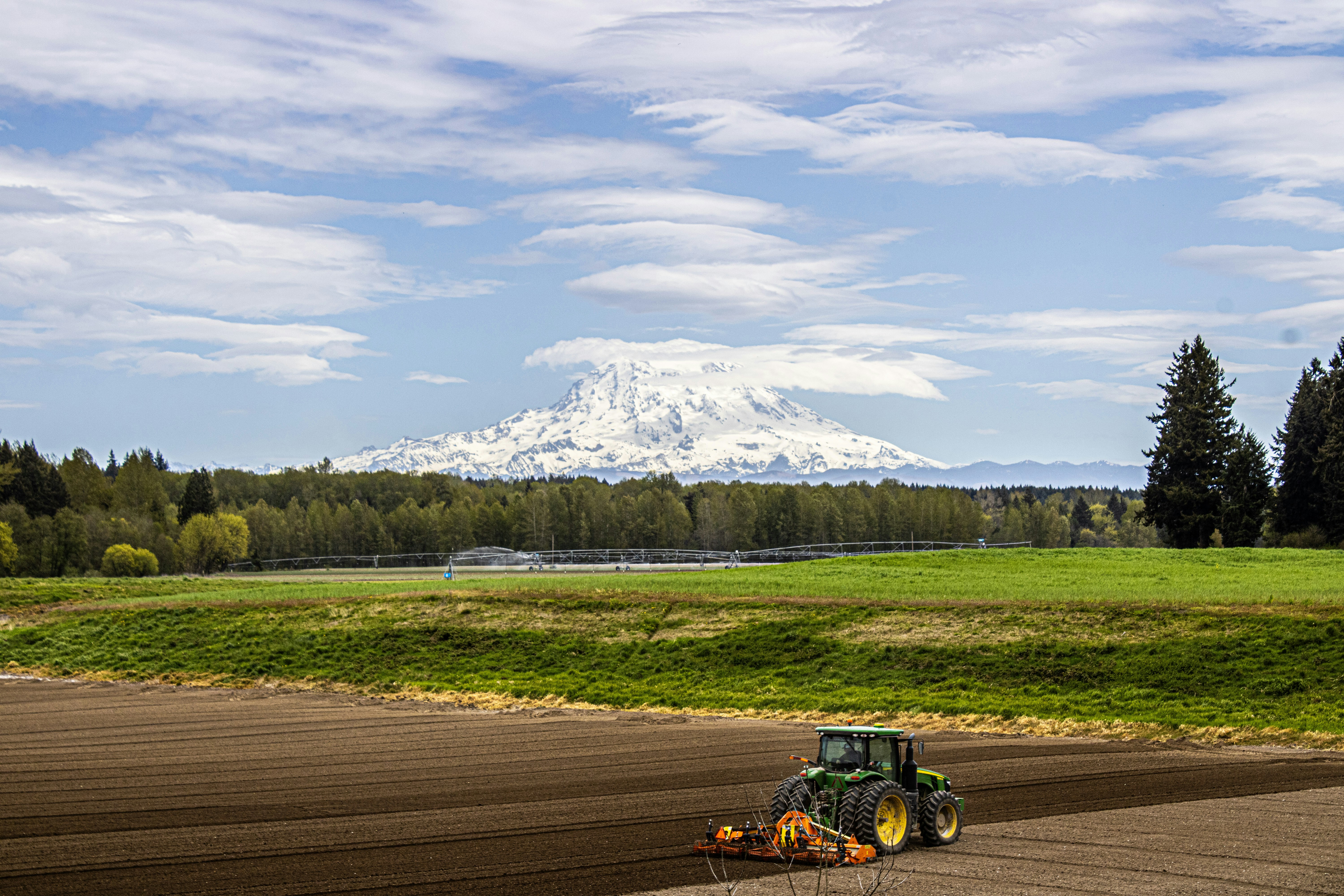 A tractor plowing a field with a mountain in the background photo ...