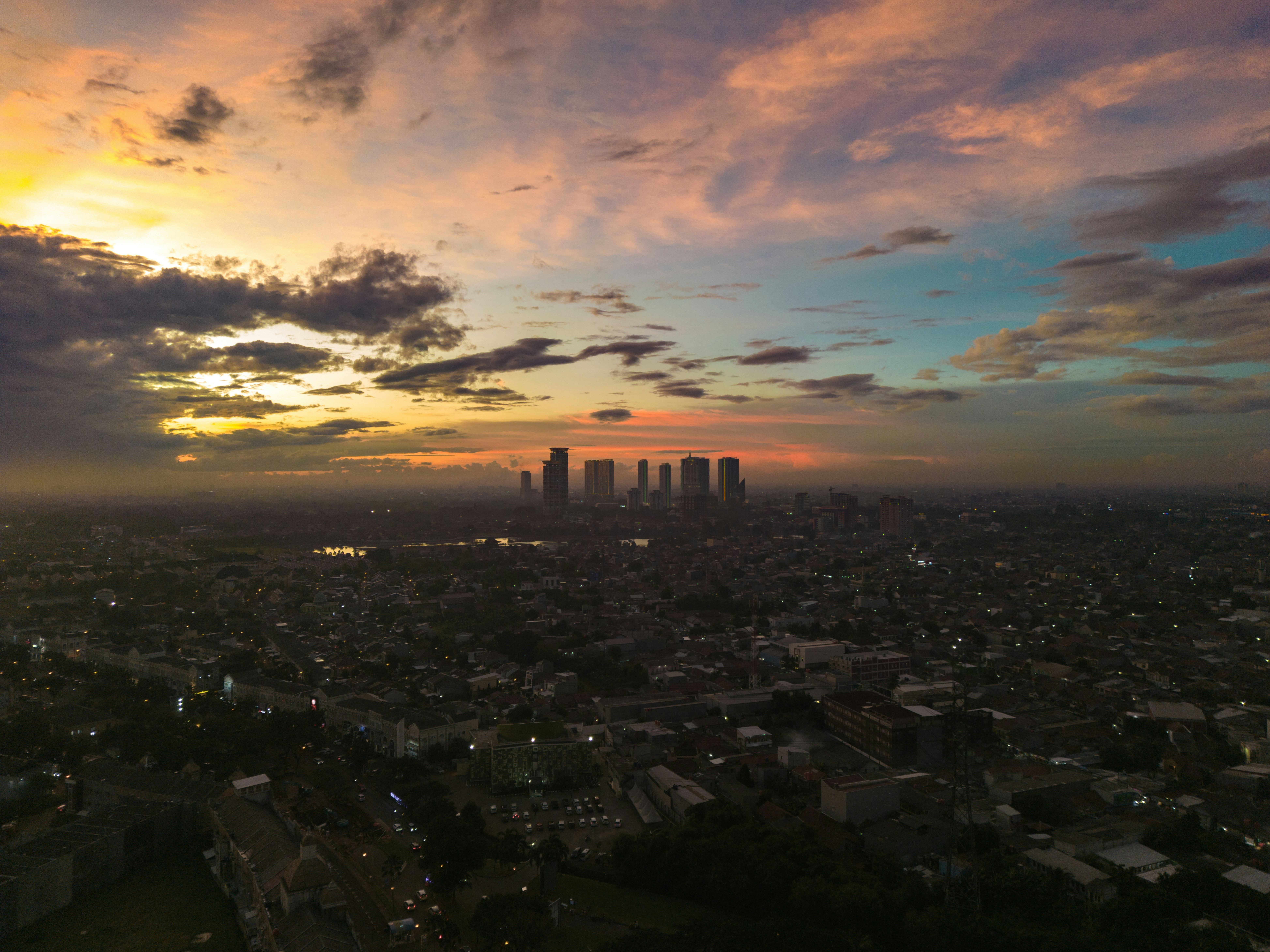 City skyline silhouetted against a vibrant sunset with dramatic clouds.