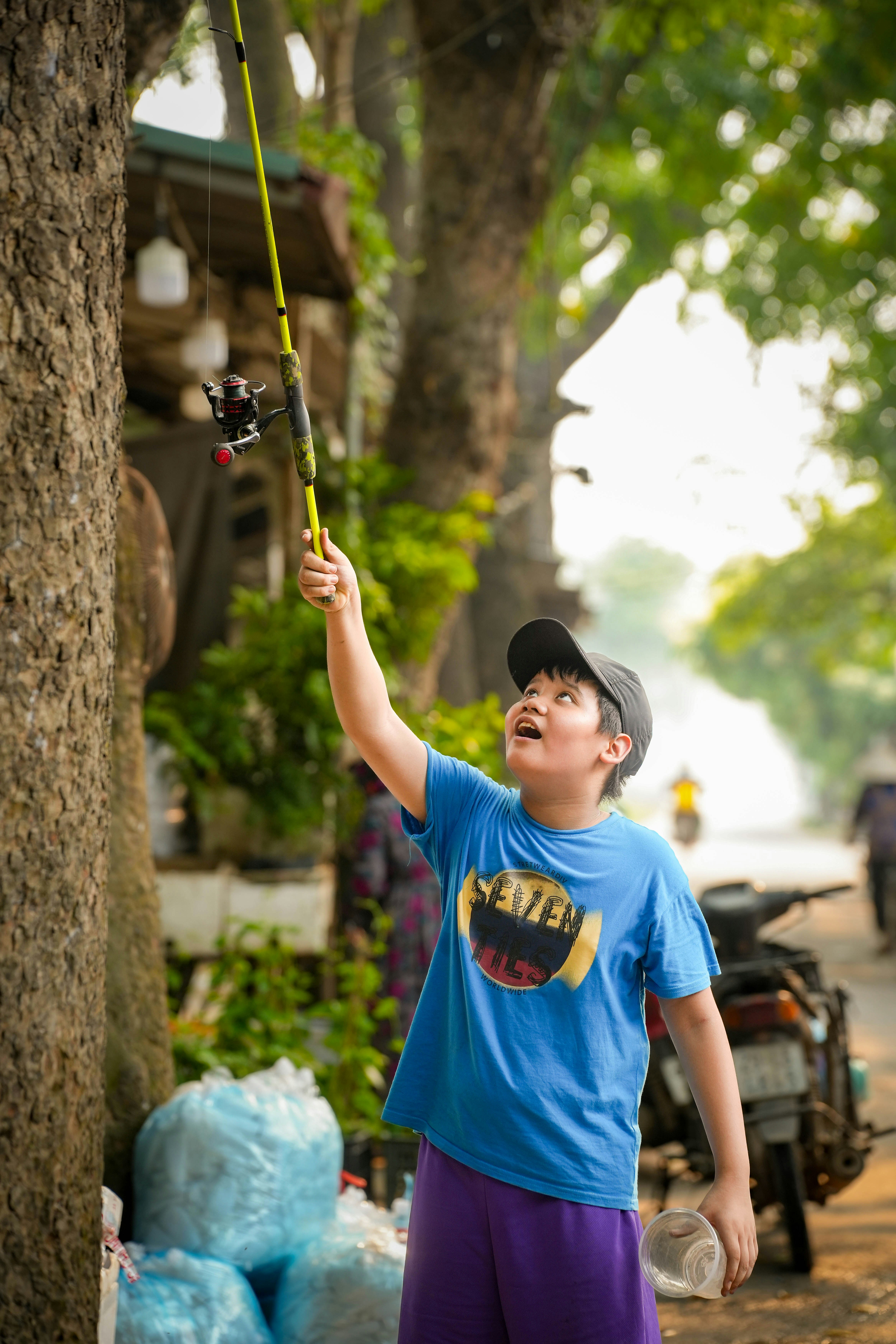 Canopy Quest: A Boy in Blue Reaches for a Fishing Line Under Sunlit Trees