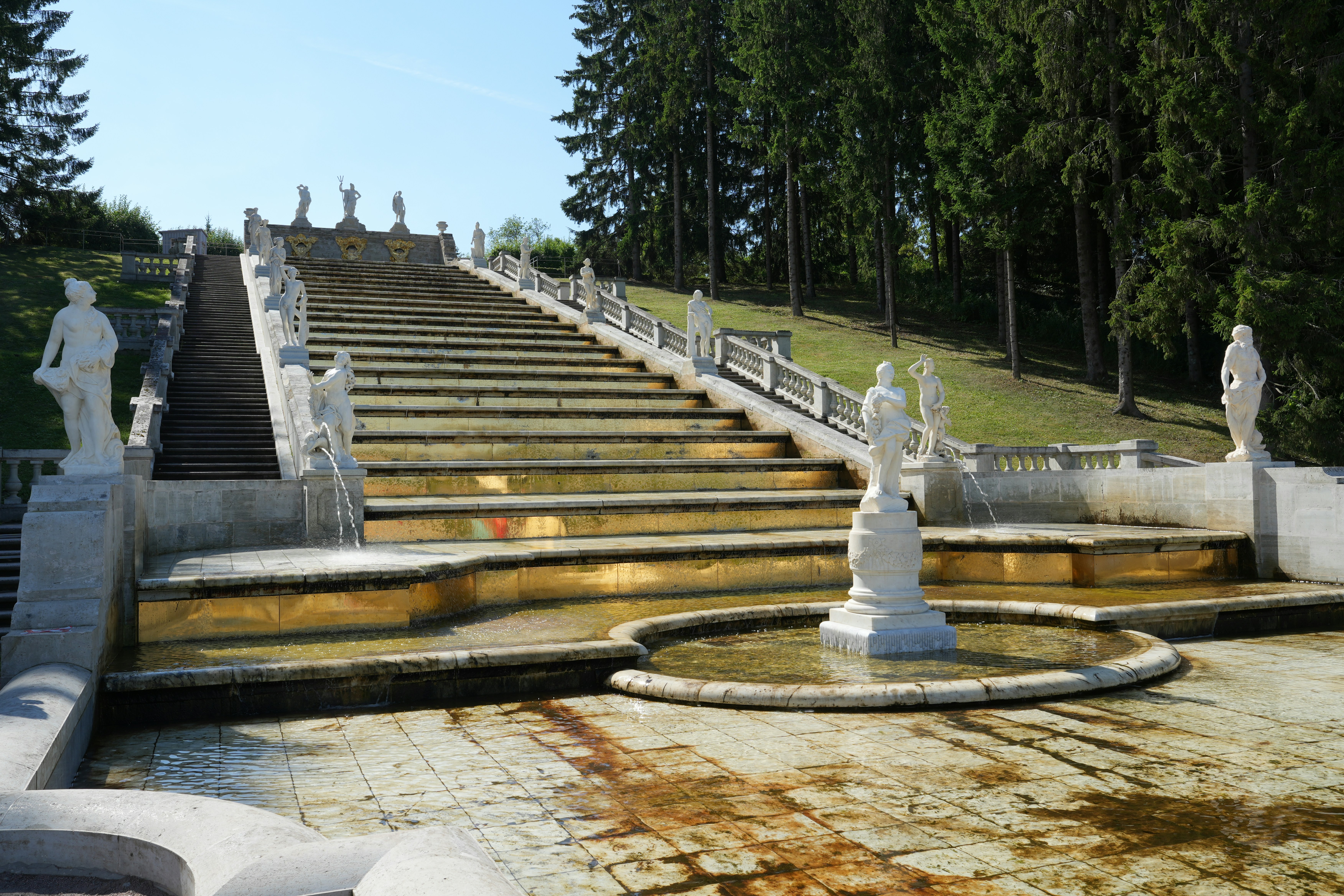 Symmetry on Stone: Grand Staircase Framed by Sculpted Figures and a Foreground Fountain