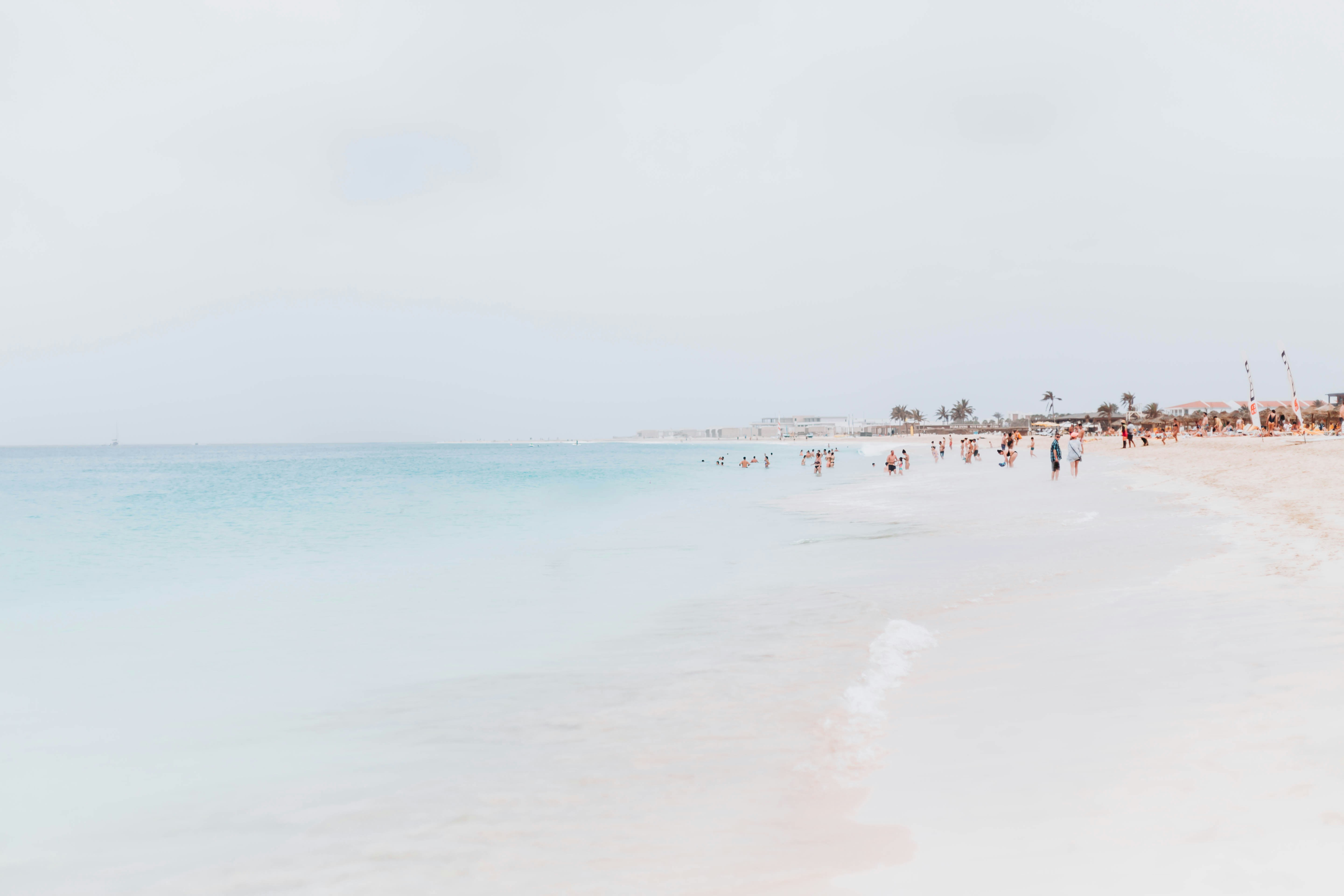Sunlit Shoreline: Distant Silhouettes along a Powdery Beach