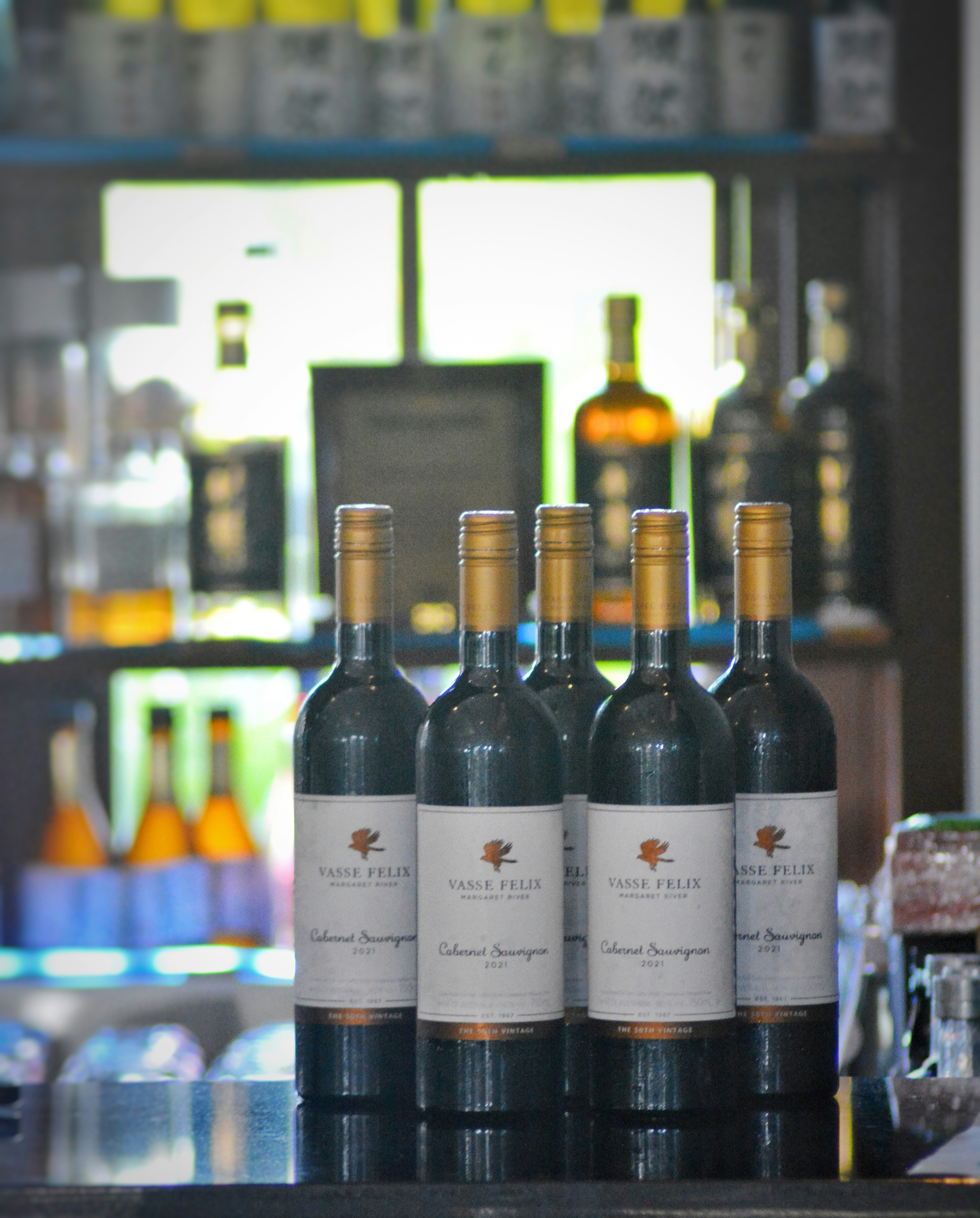 Three bottles of wine are sitting on a bar photo – Free Wine bottle ...