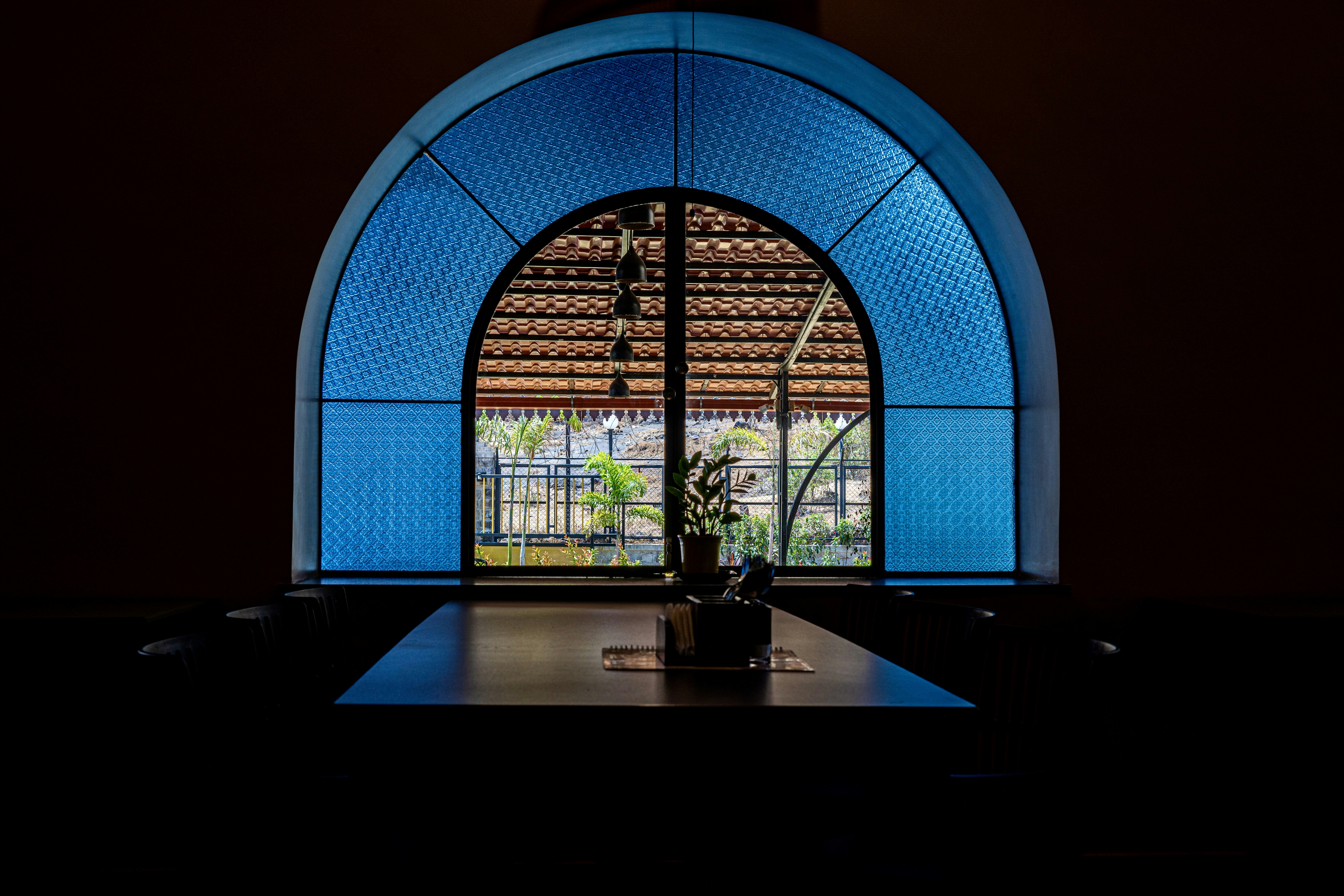 Blue Archway Café Window: Quiet Light Through a Midnight Interior