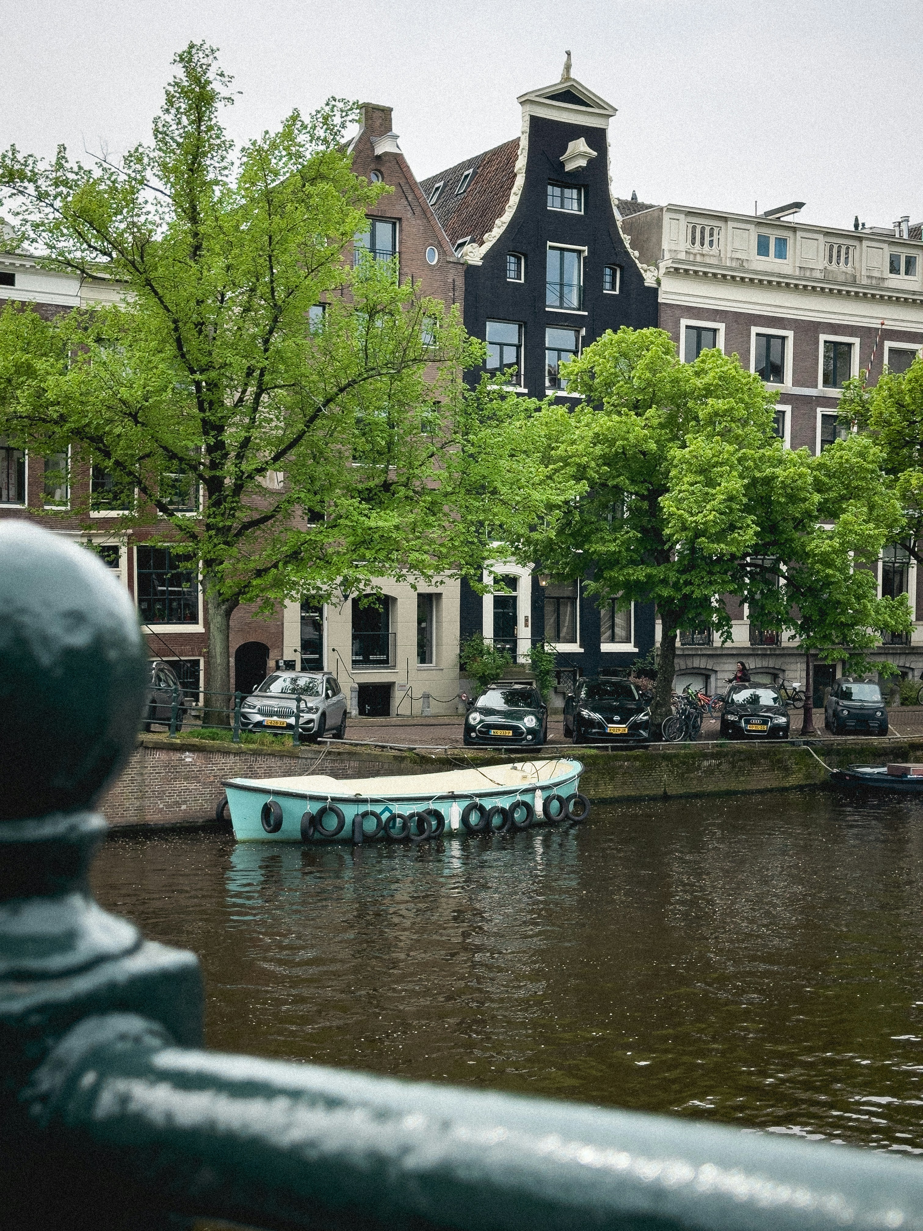 Green Canalside: Trees, Boat, and Historic Facades Along the Water