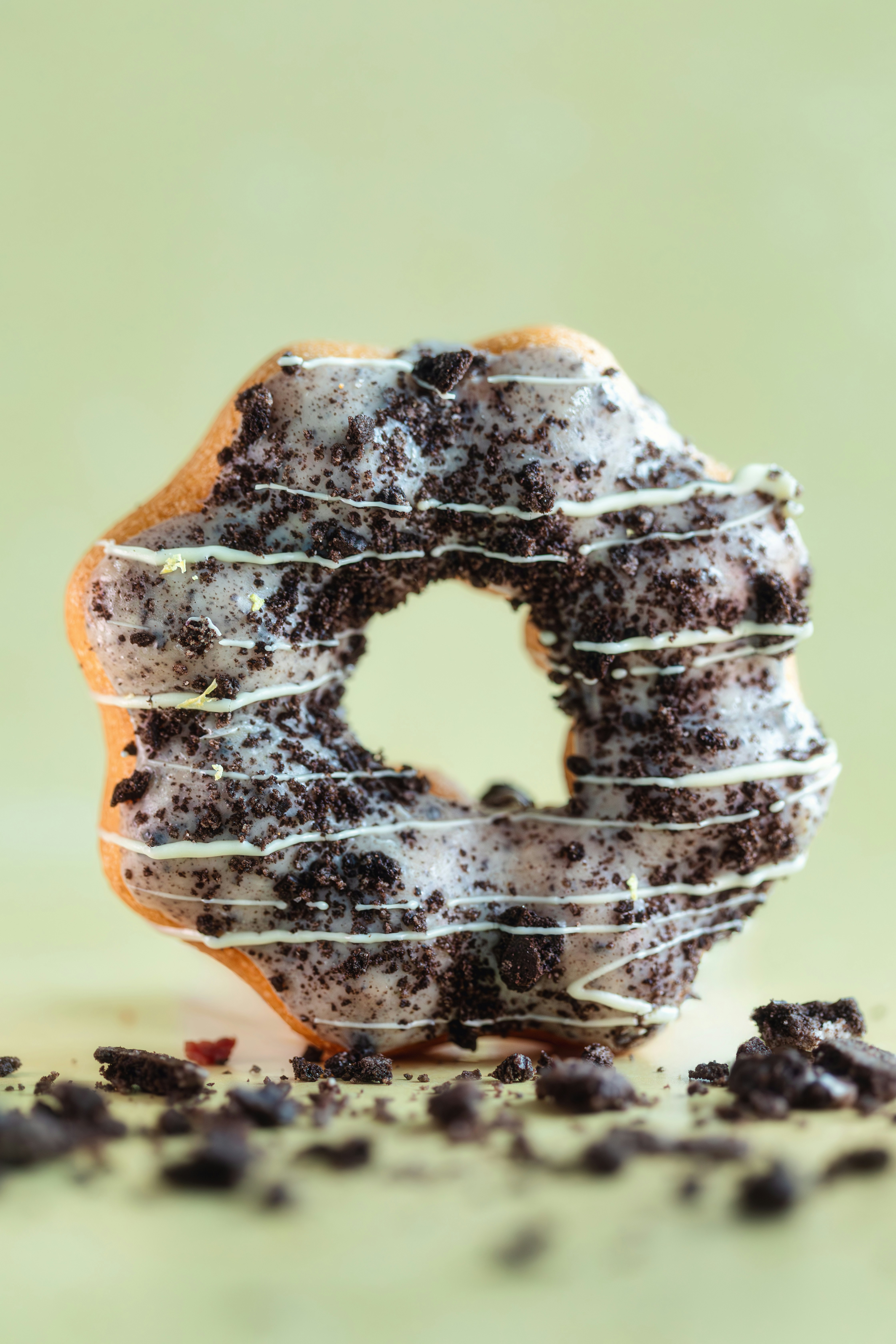 Cracked Oreo Donut with White Chocolate Drizzle on a Soft Focus Green Backdrop