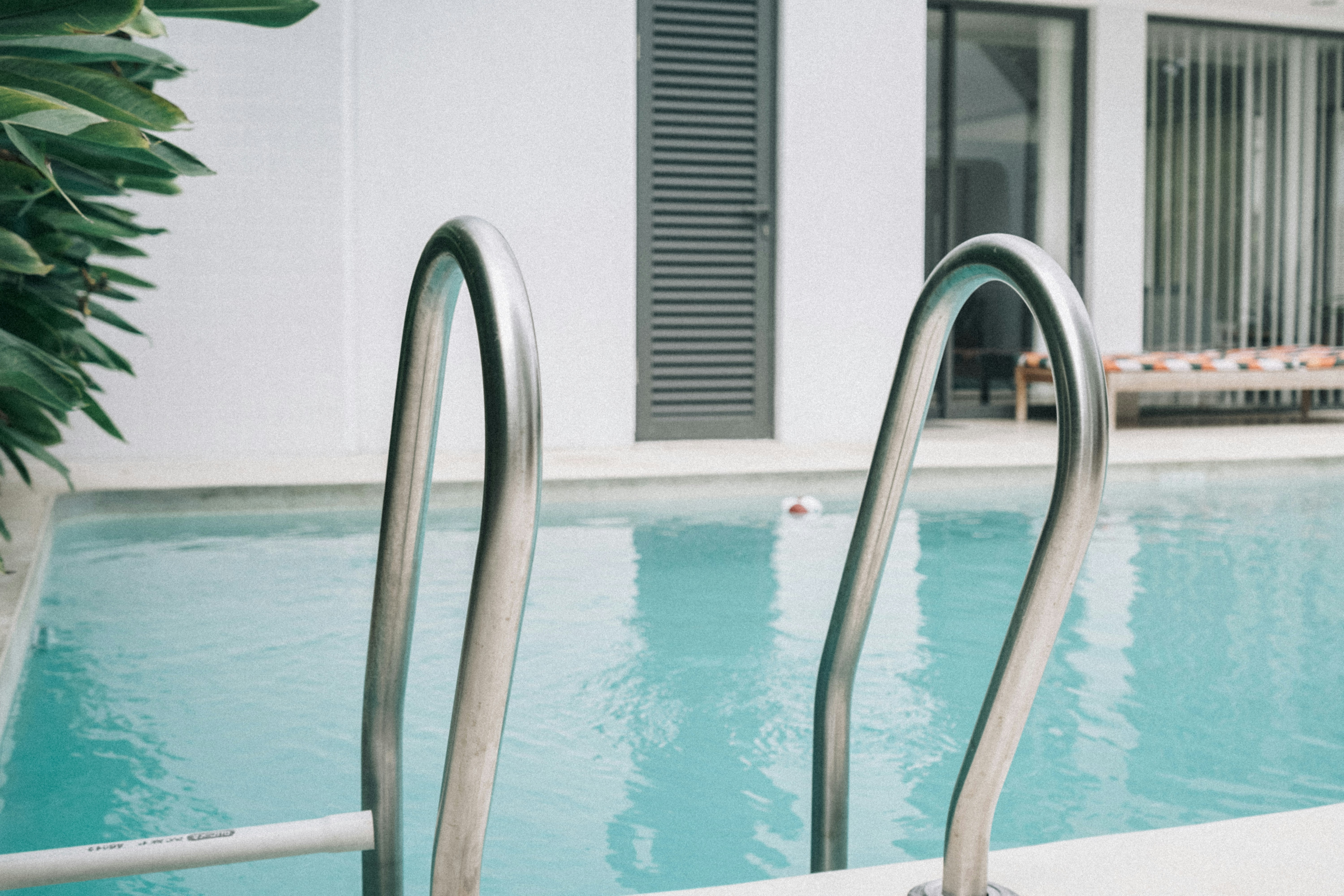 A swimming pool with a metal hand rail next to it photo – Free ...