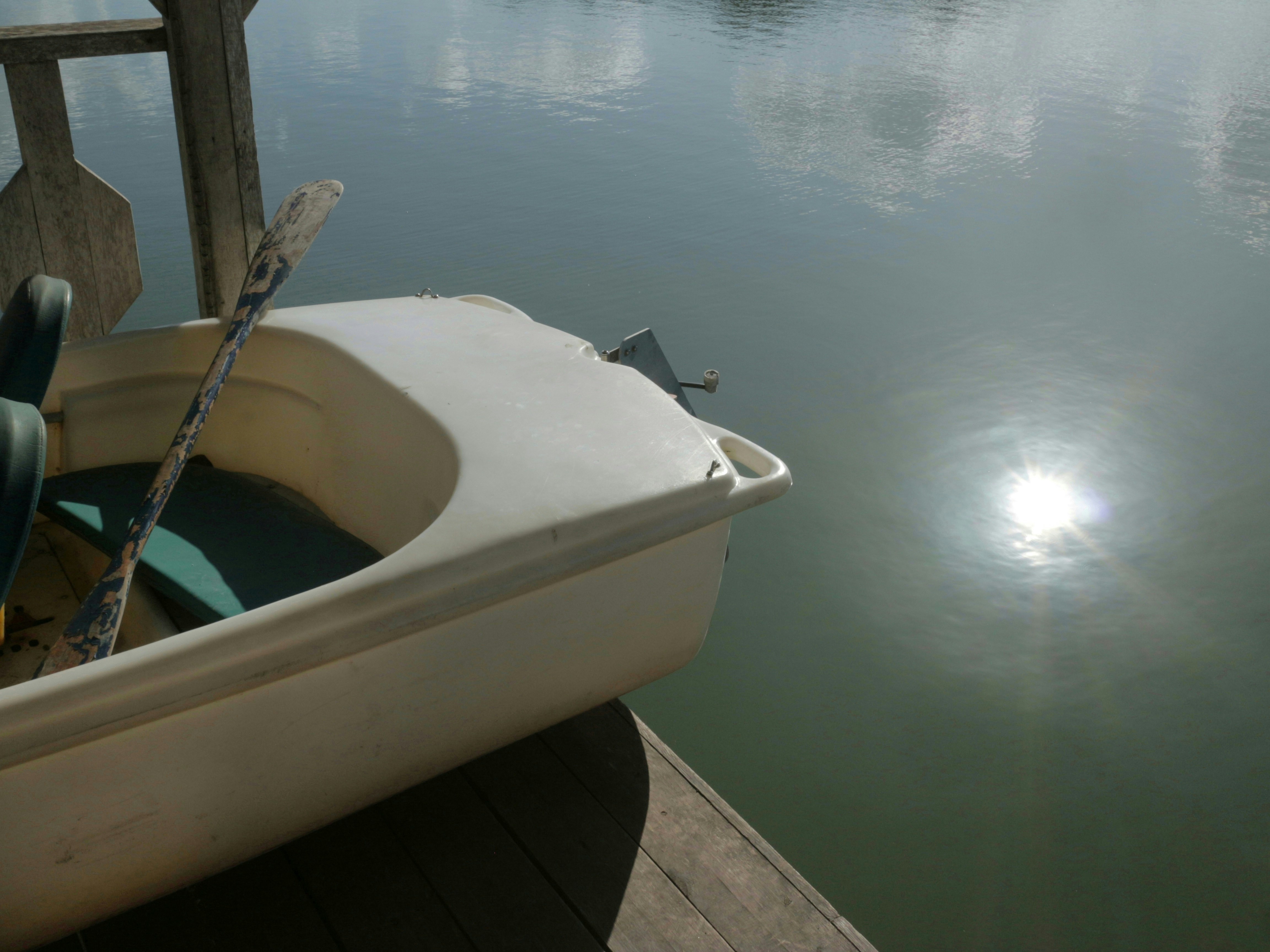 Glassy Harbor Moment: A Docked Rowboat Quietly Reposes by Sunlit Water