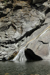 Sunlit Vein Lines on a Granite Cliff Over Quiet Waters