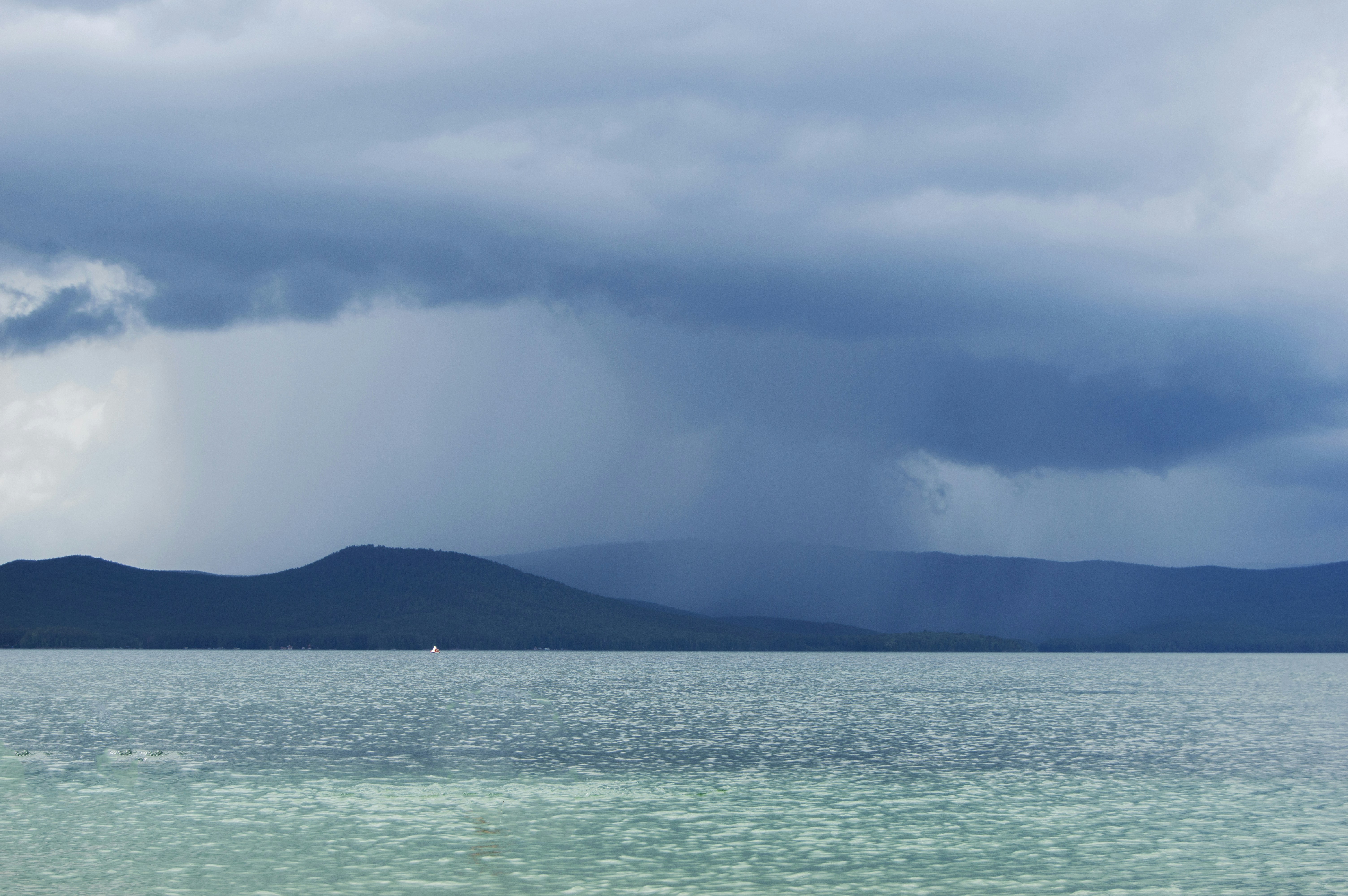 Storm Over the Sea: Distant Dunes and Calm Green Water