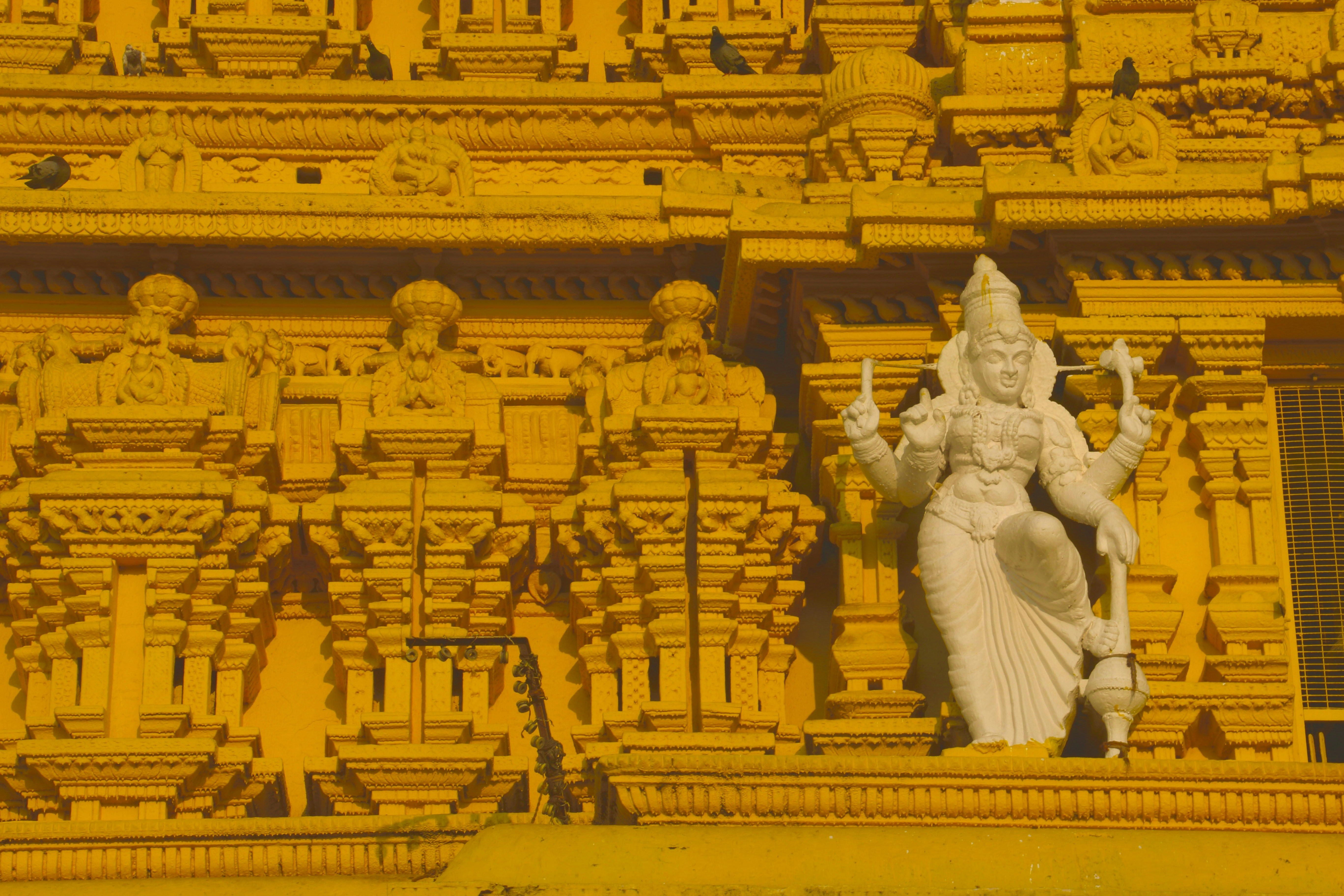 A statue of a god in front of a yellow building photo – Free Woman ...