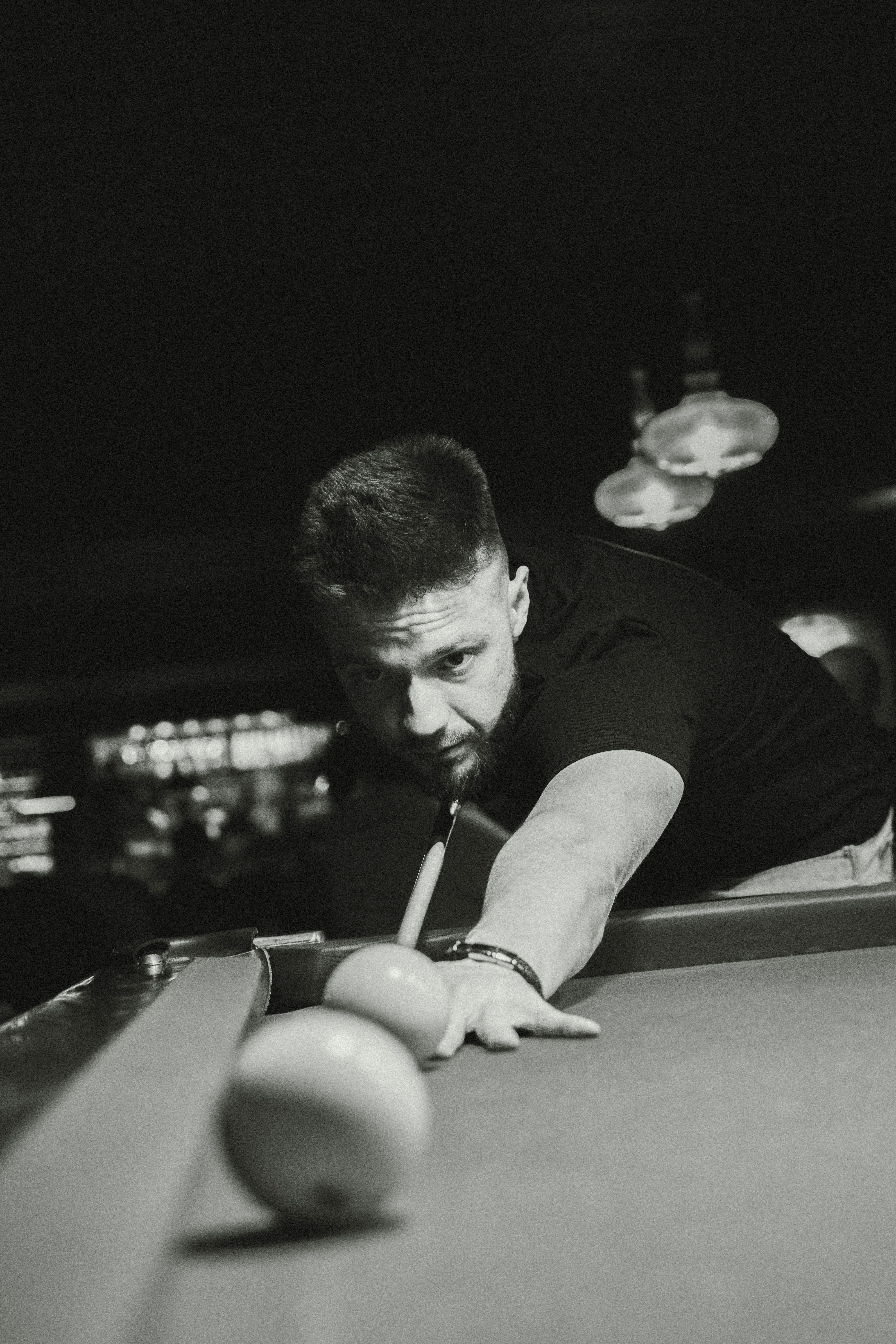 Under Neon Quiet: A Pool Player's Focus in Black and White