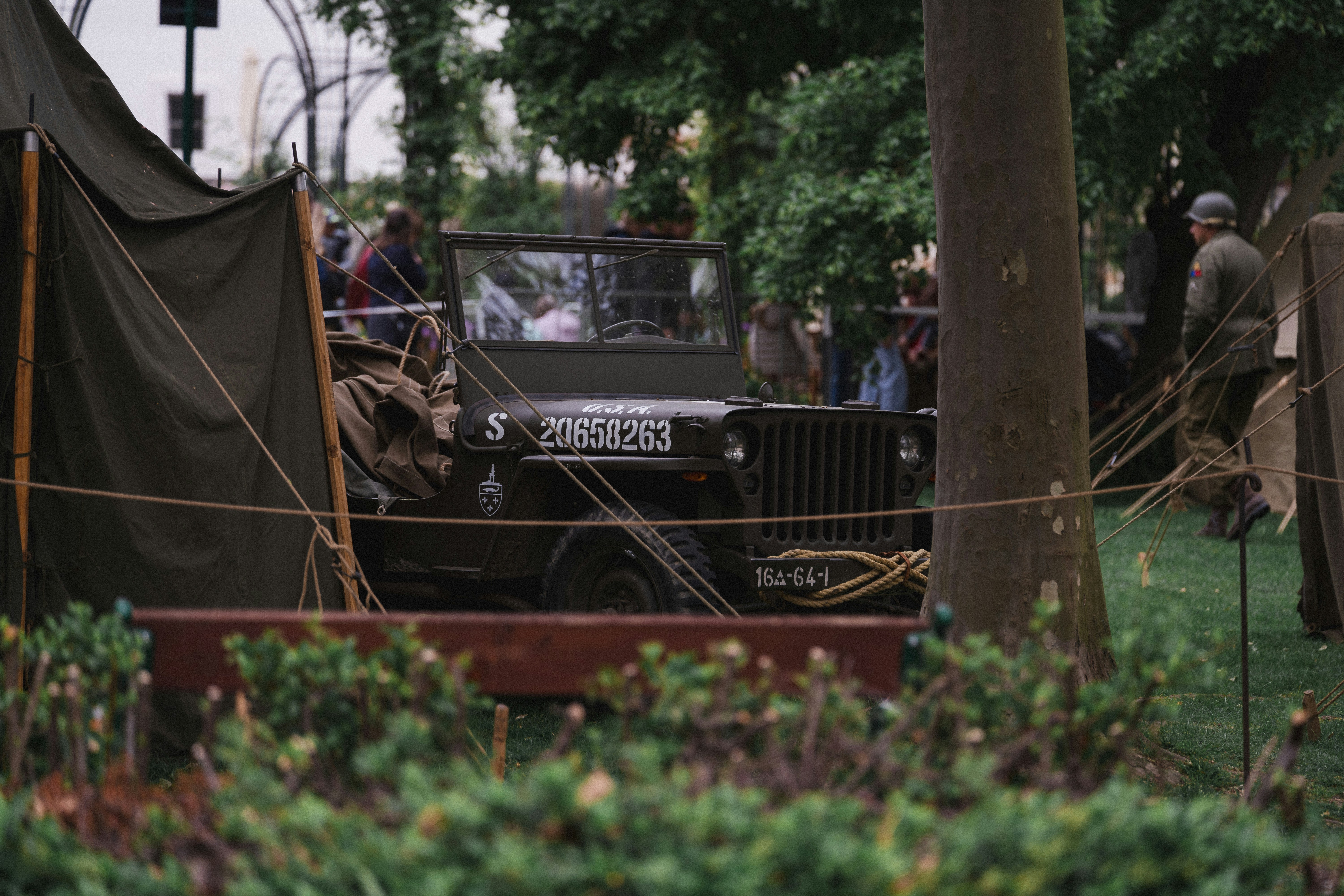 Jeep at Rest in a WWII Camp: Tents, Spectators, and a Quiet Historic Moment