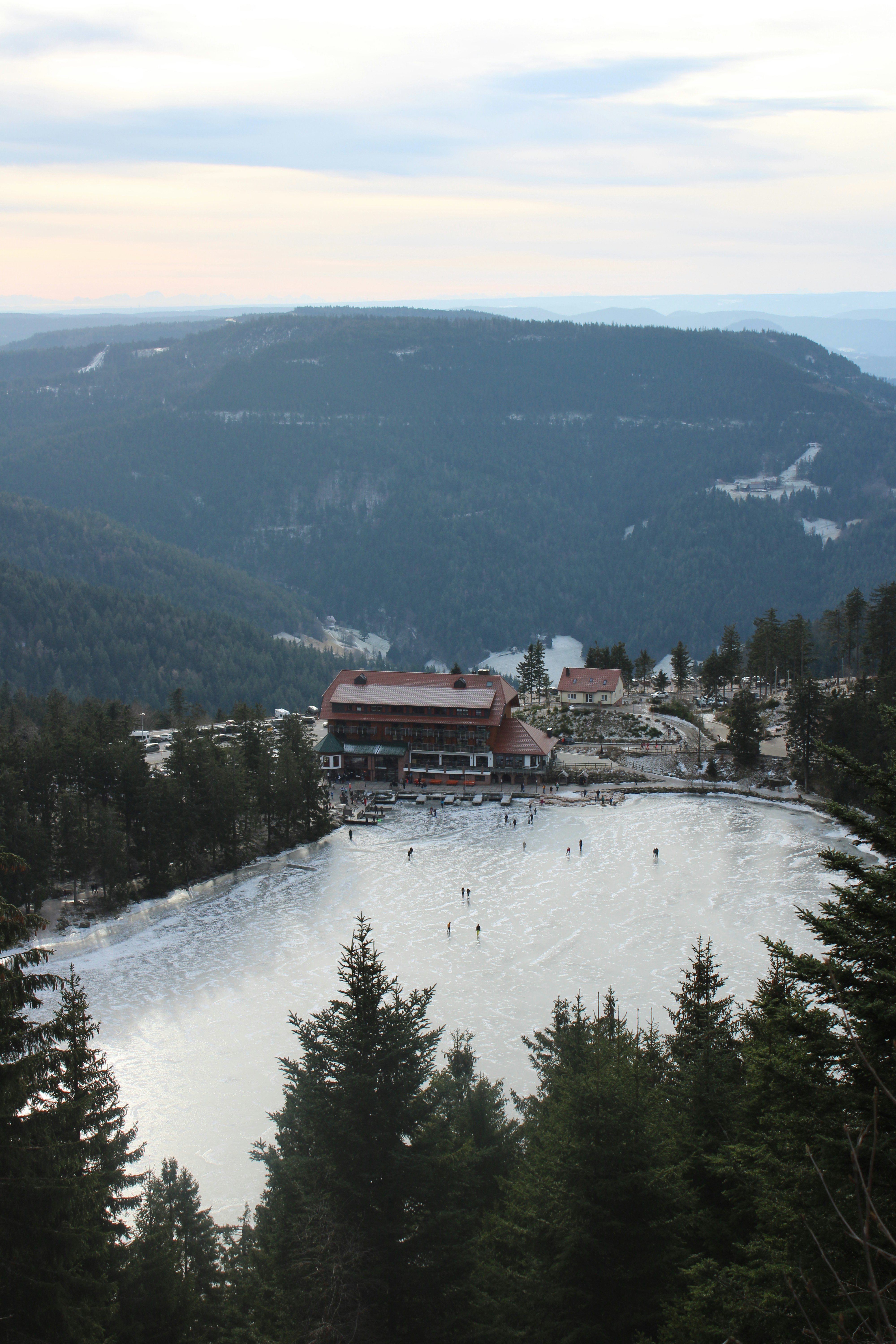 Skaters on a Frozen Alpine Pond Framed by a Rustic Mountain Lodge
