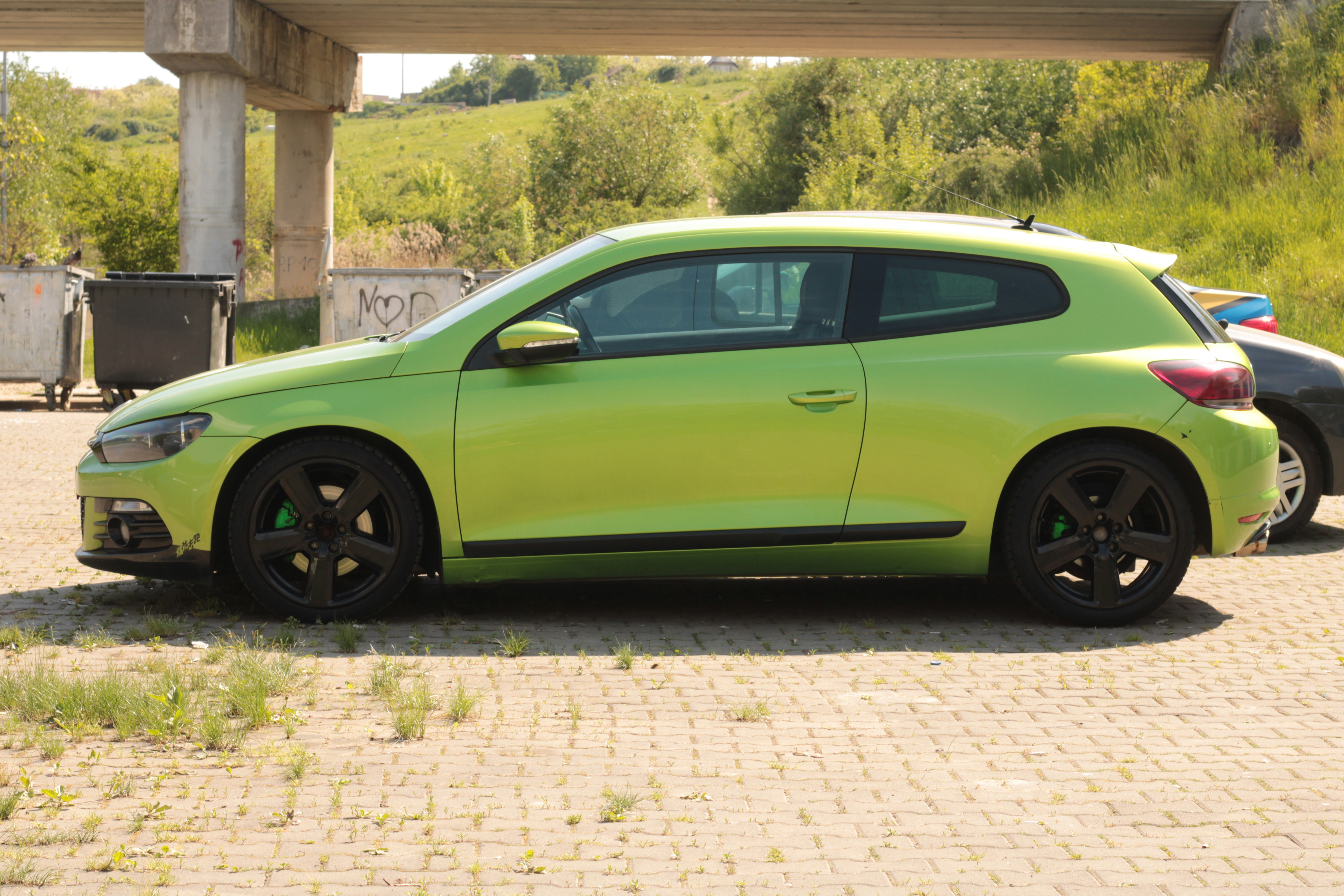 Verdant Velocity: Lime Hatchback Resting Under a Concrete Overpass
