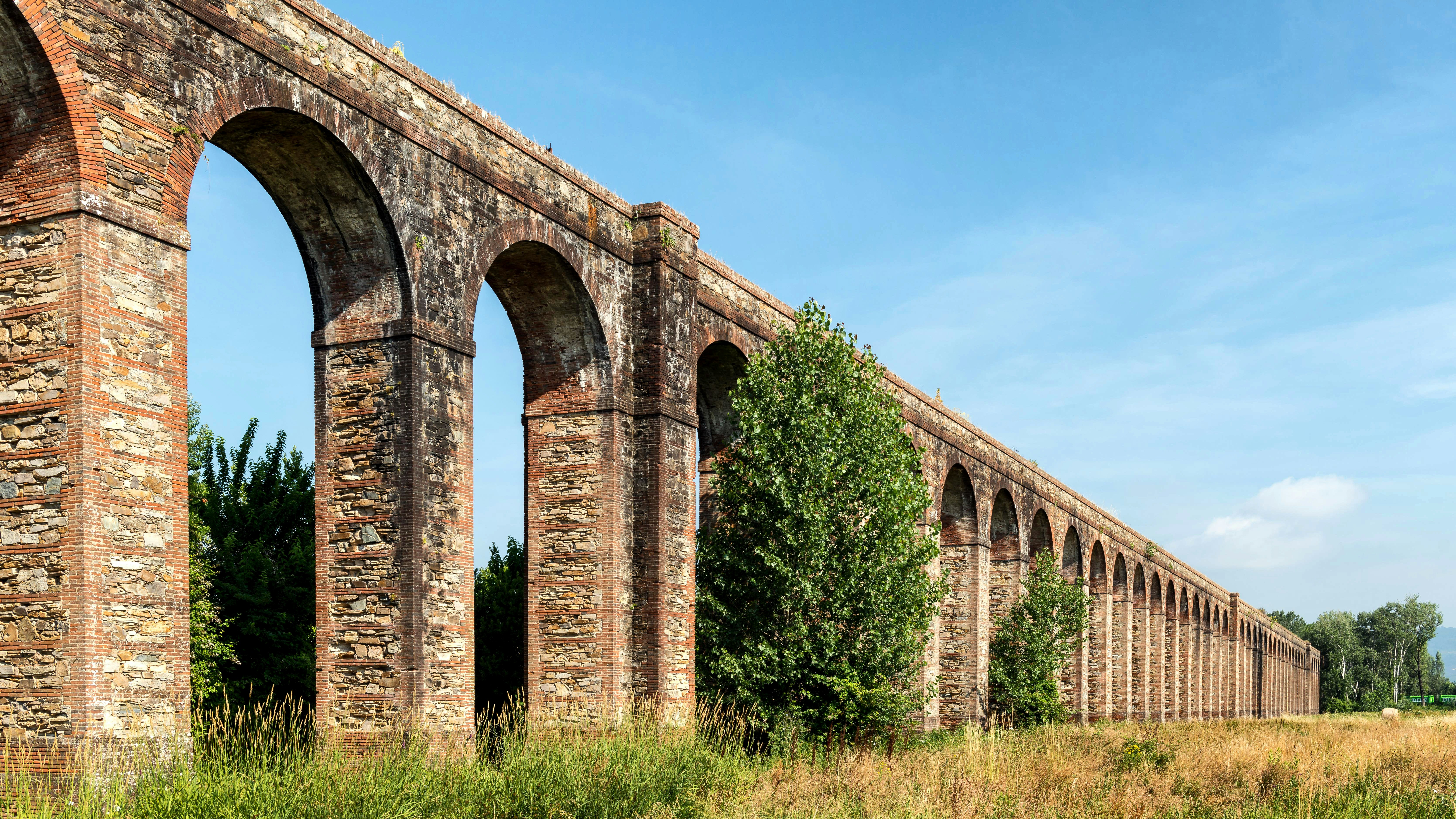 an old brick train bridge over a grassy field