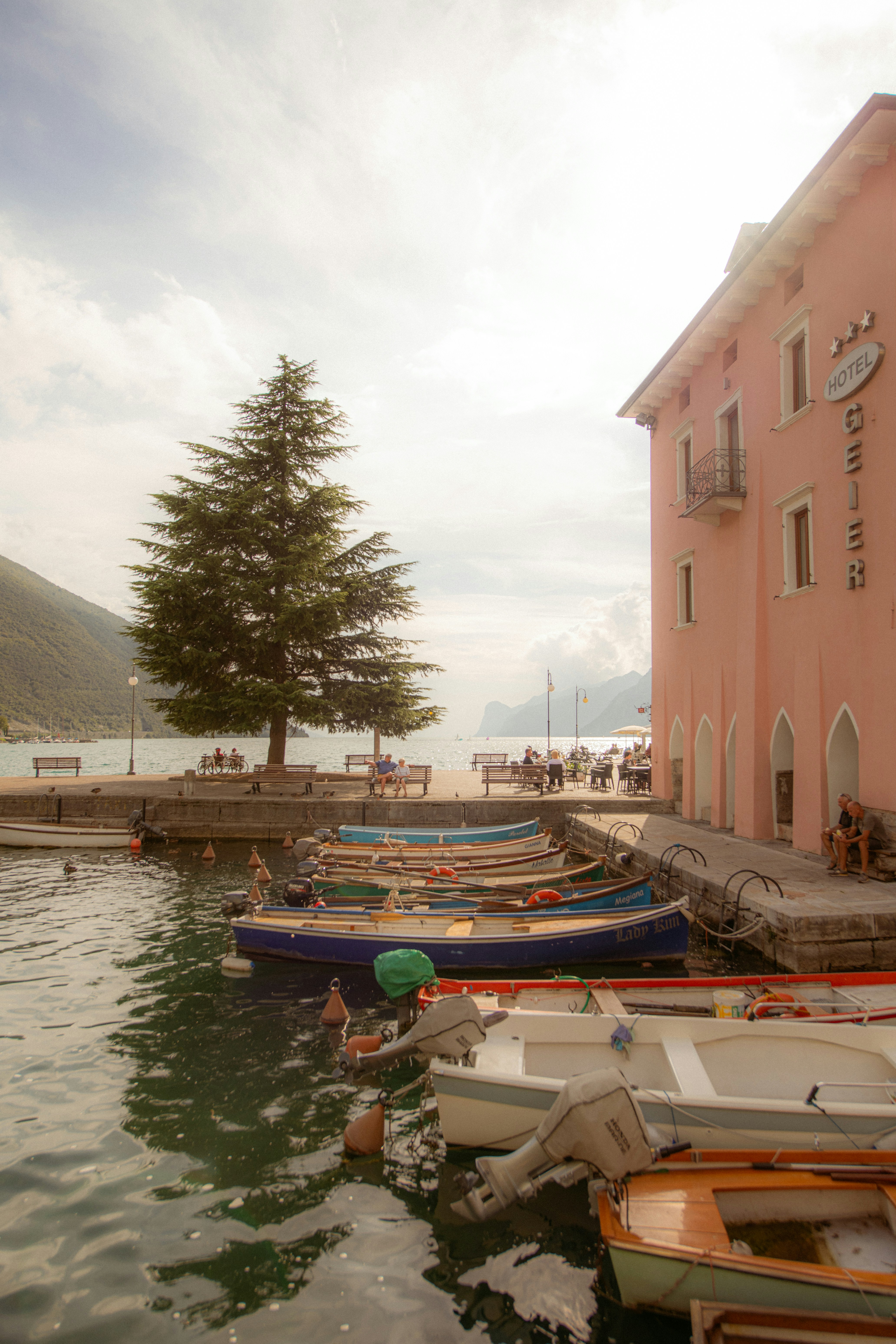 Blush Harbor: Boats, Pine, and a Lakeside Hotel by Sunlit Waters