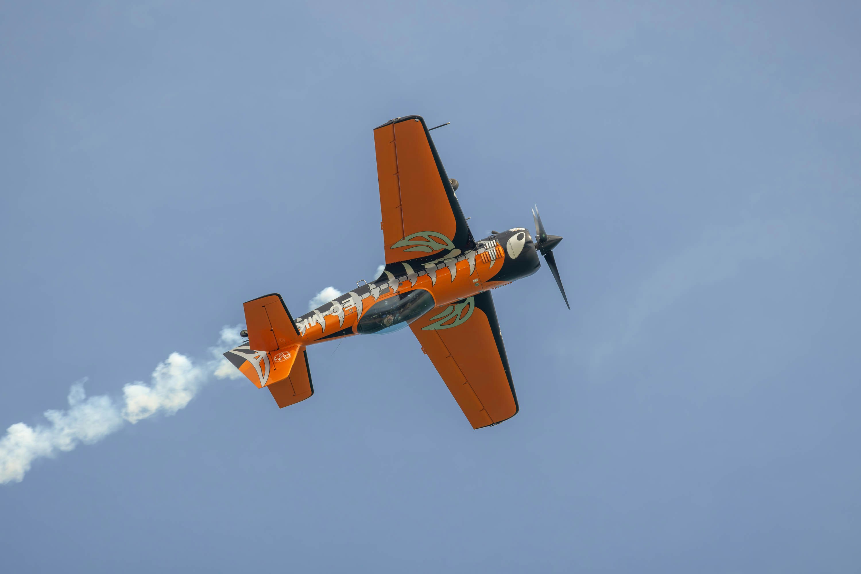 A small orange airplane flying through a blue sky photo – Free Caorle ...