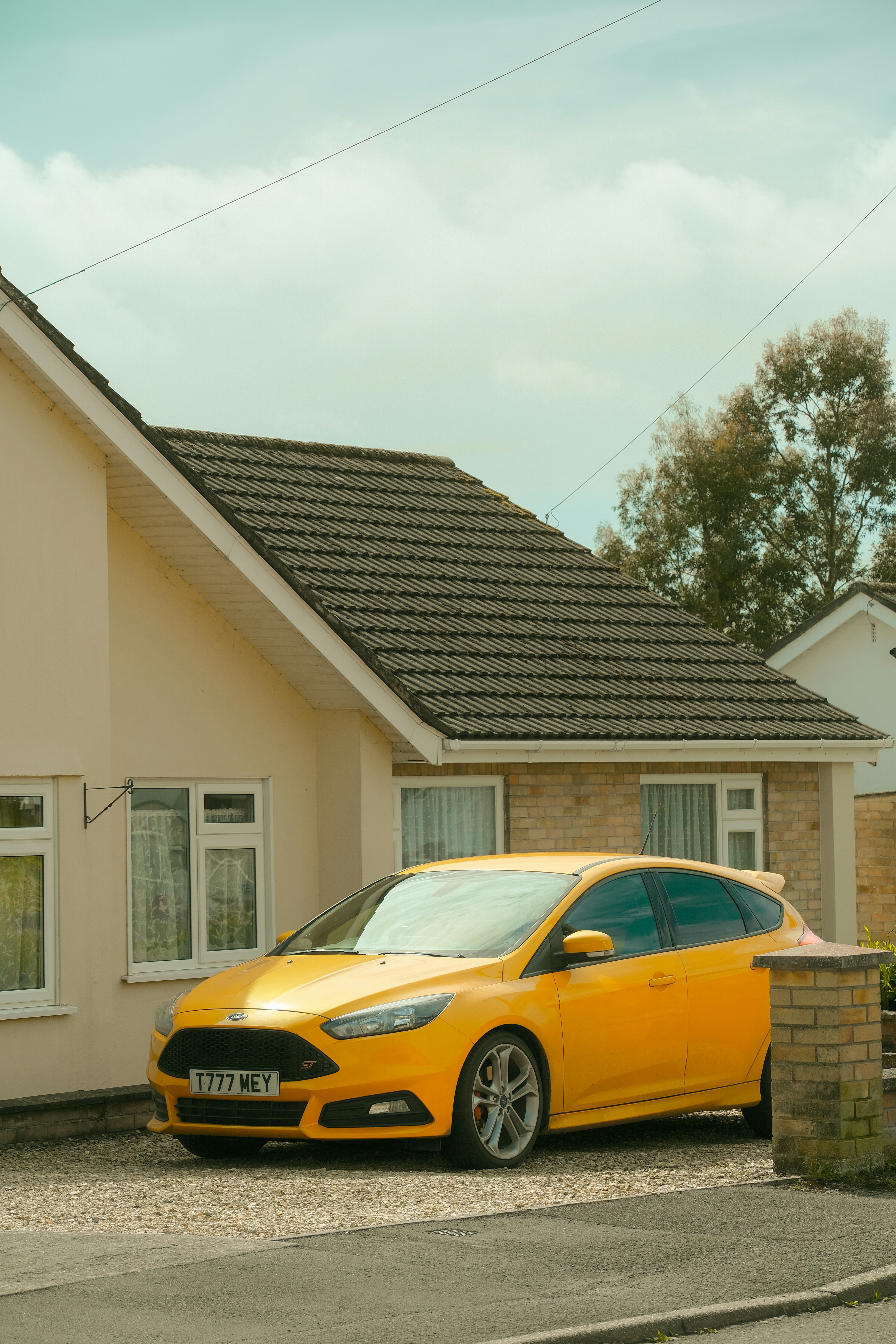 Sunlit Yellow Hatchback Anchors a Quiet Suburban Driveway
