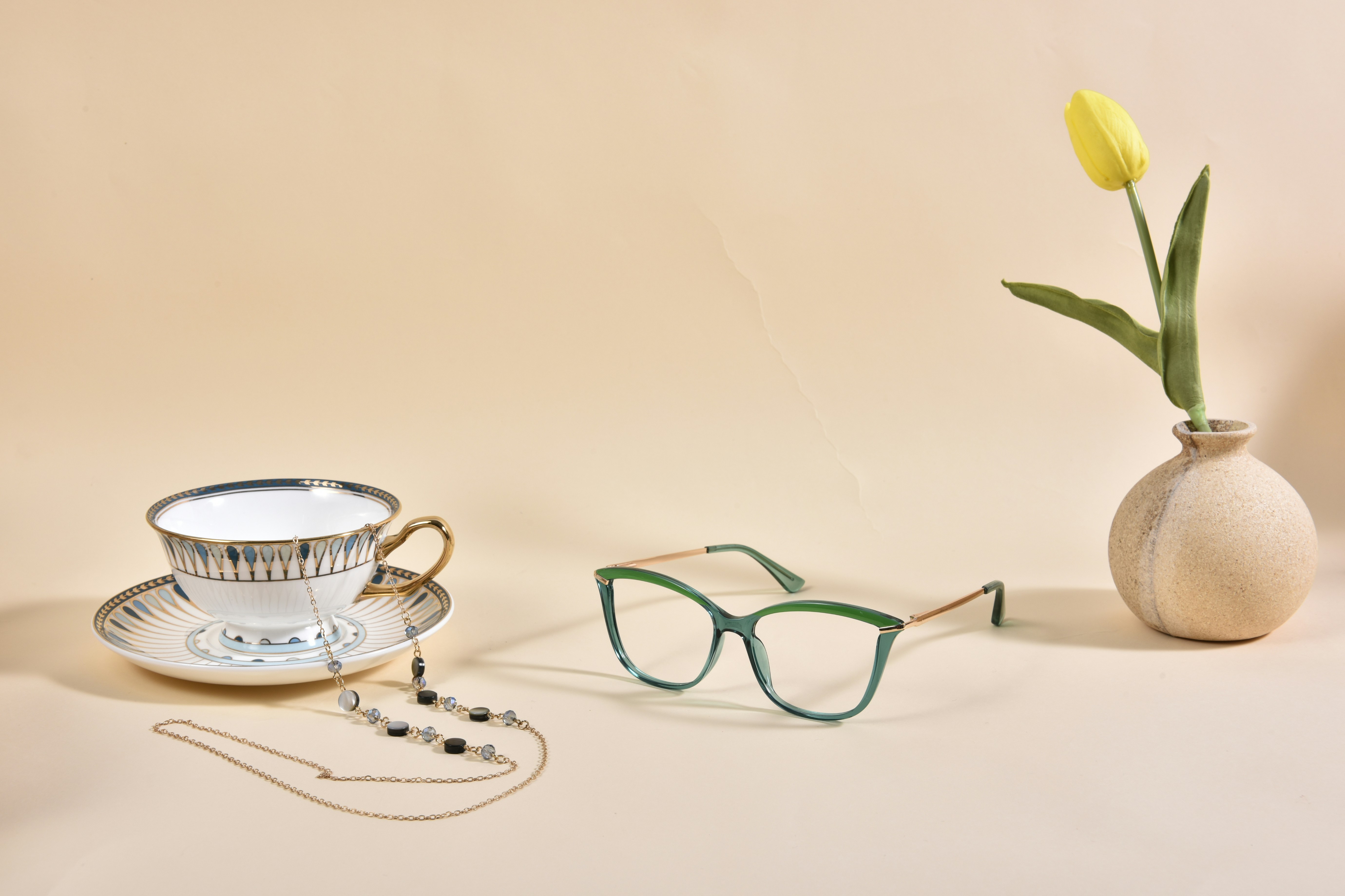 On the table lies a pair of emerald green cat-eye glasses, nestled beside a delicate teacup and a quaint flower vase. The scene exudes tranquility and comfort, inviting one to envision a leisurely afternoon ahead. The ambiance seems to promise a delightful respite, beckoning one to indulge in the simple pleasures of life.