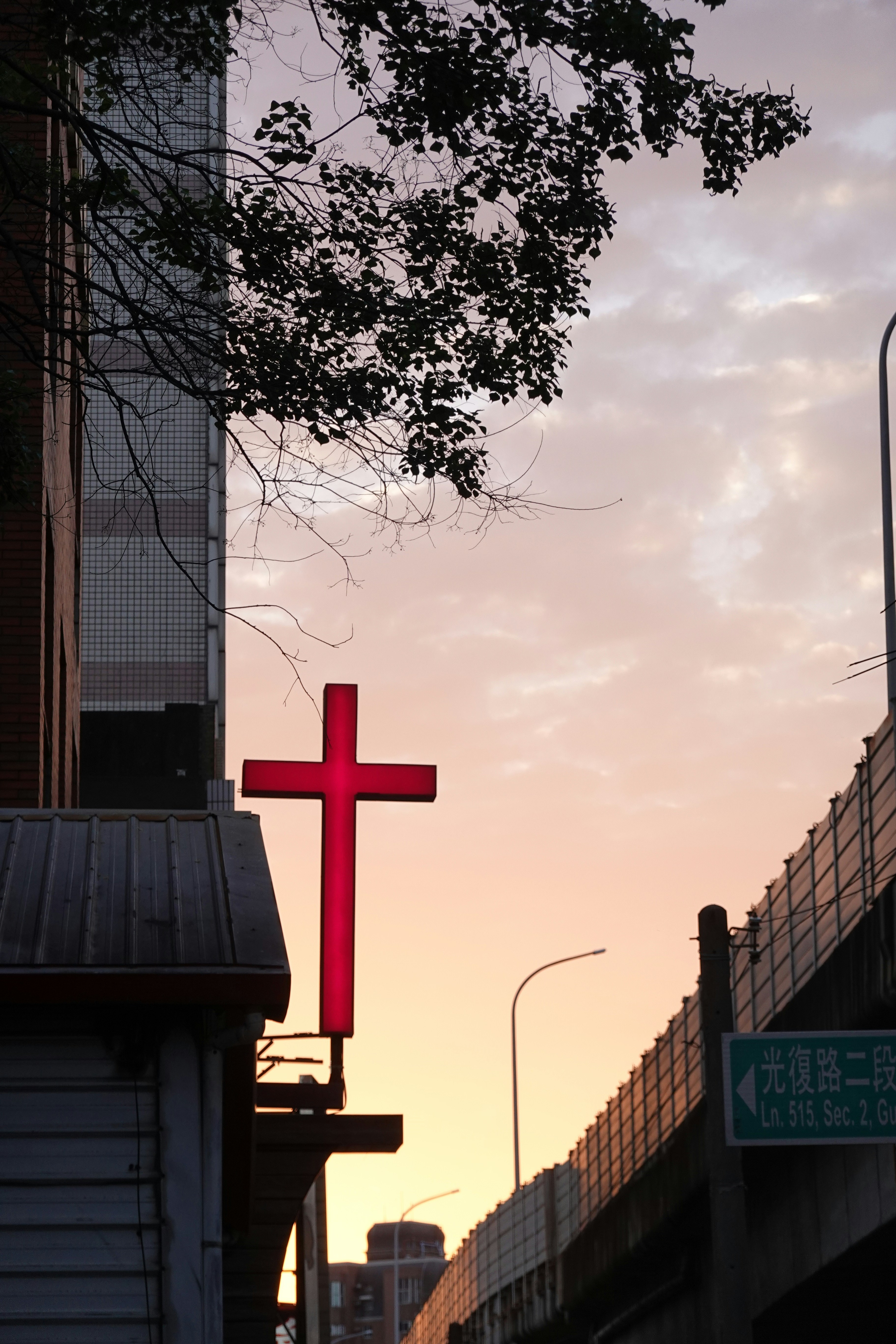 Cruciform Neon at Dusk: Neon Sign Anchors a Quiet City Sunset