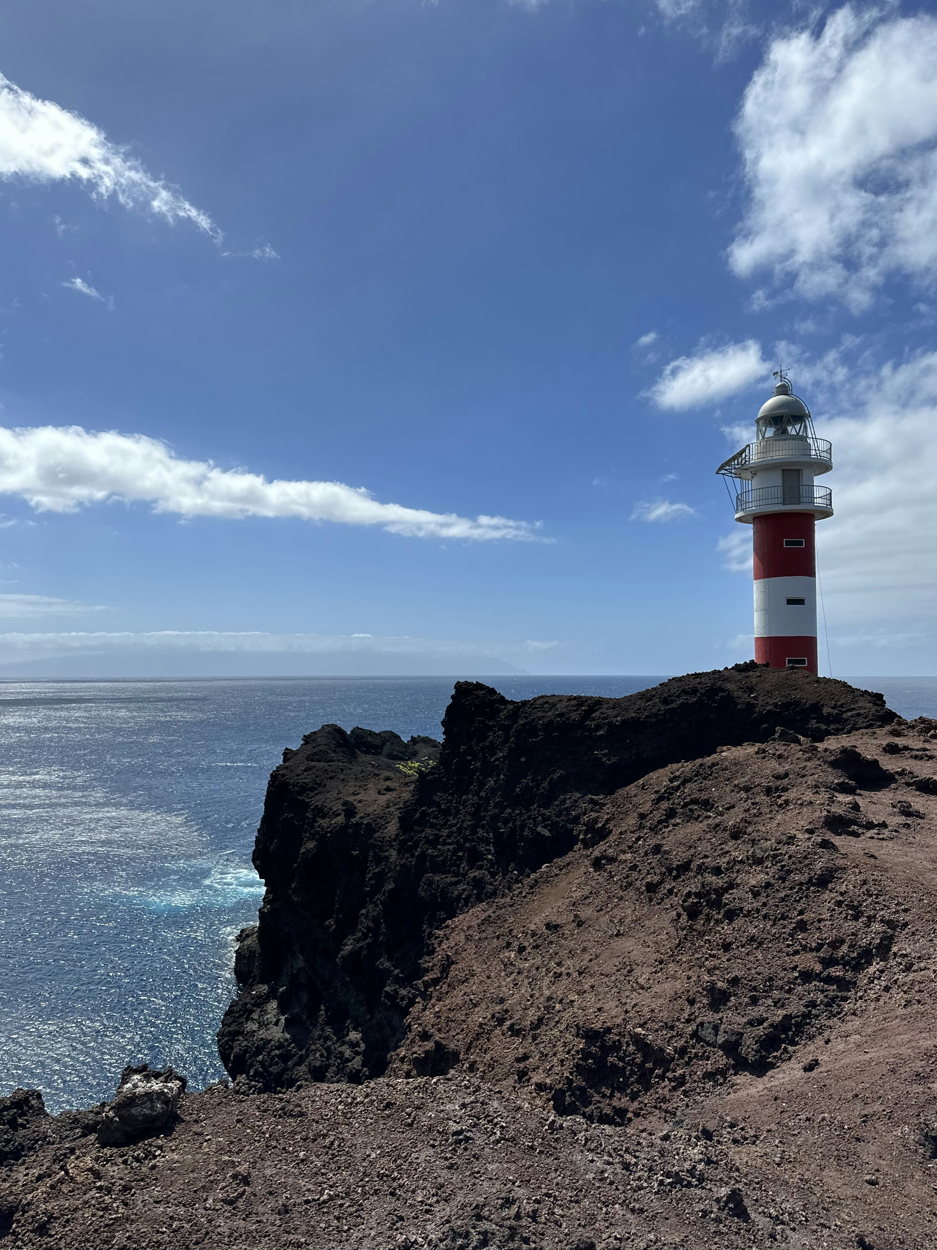 Red-and-White Lighthouse Standing Guard Over Rugged Lava Rocks