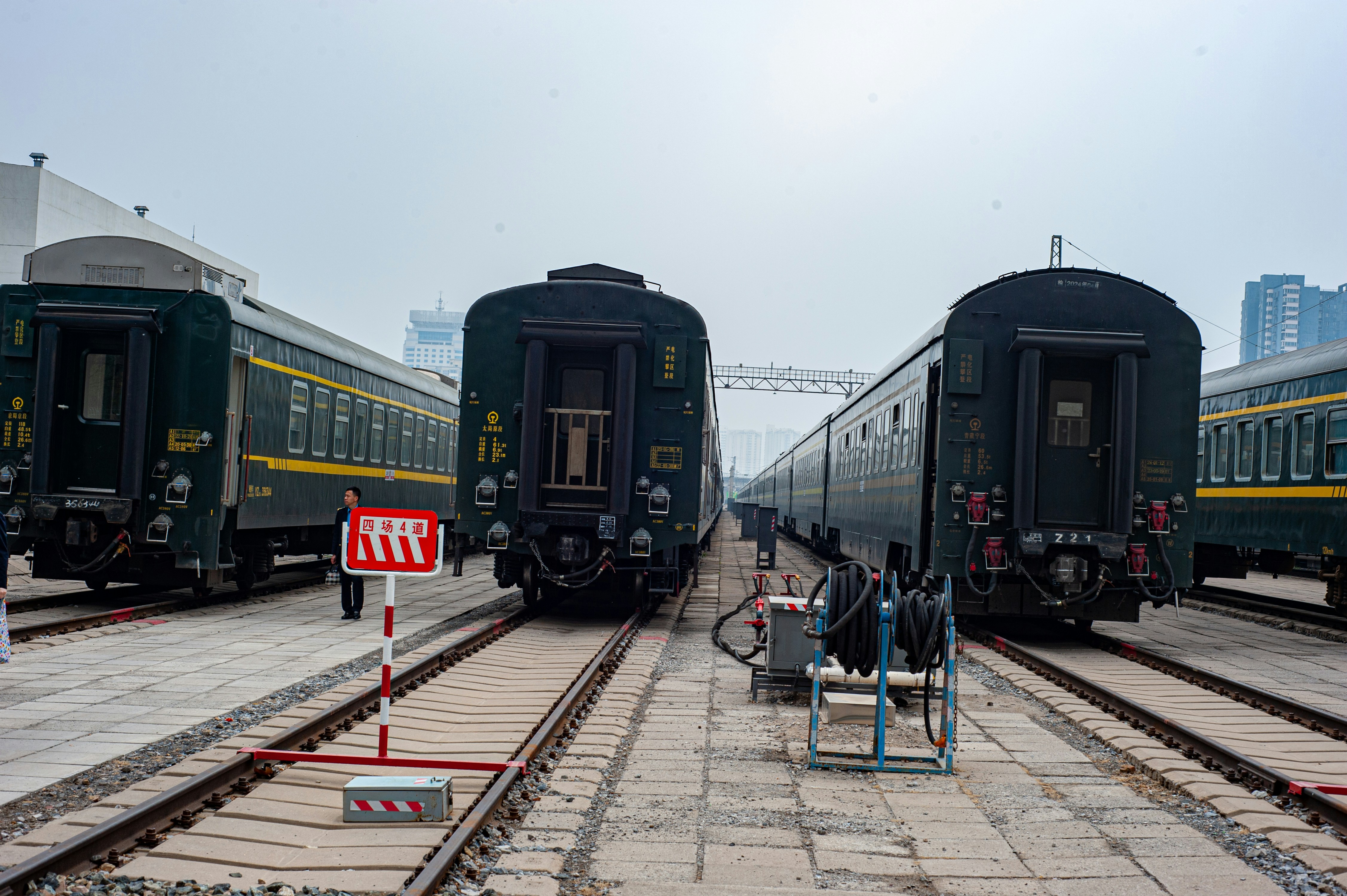 Center Stage in a Quiet Rail Yard: Three Green Carriages Between Tracks