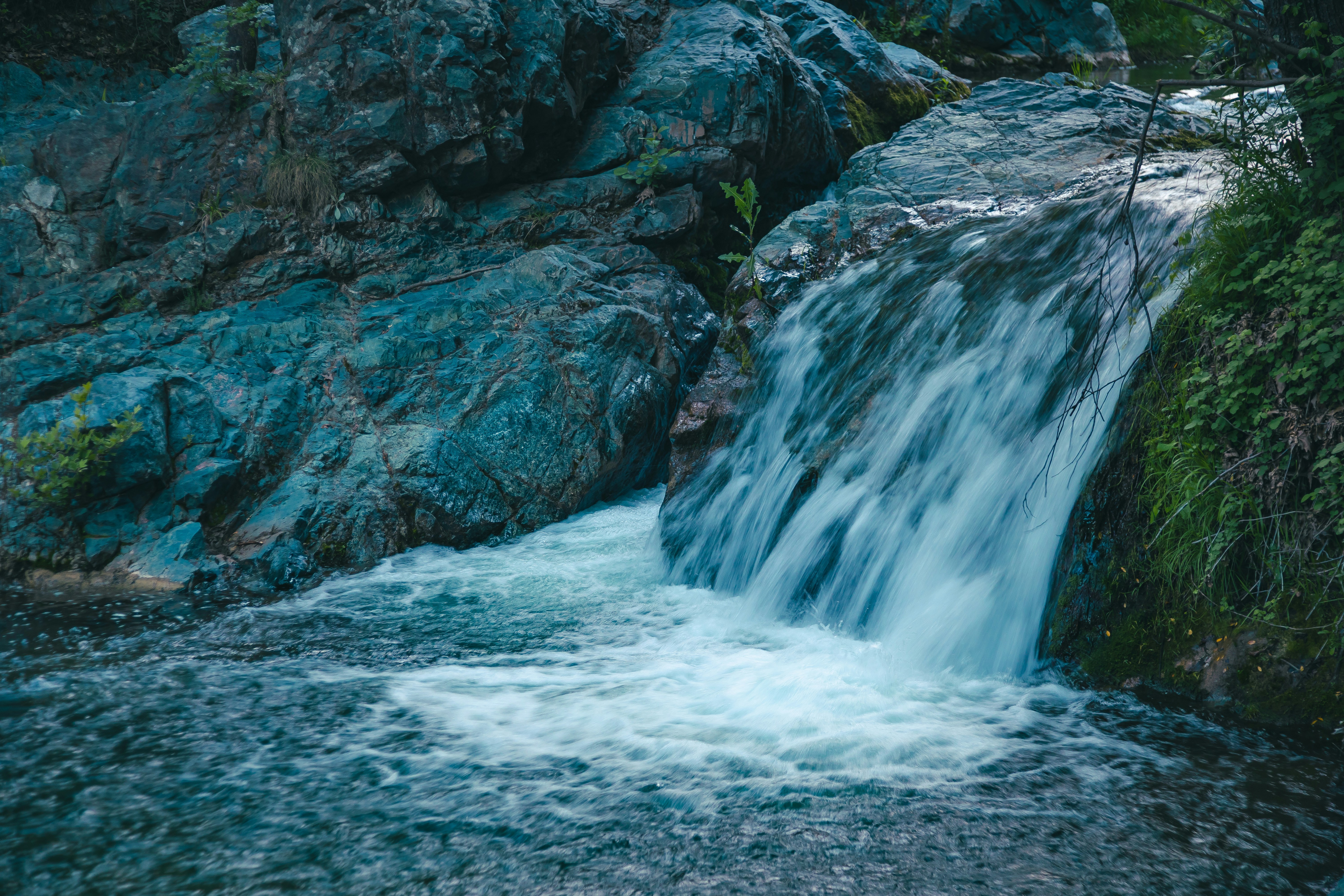 A small waterfall flowing over rocks into a river photo – Free ...