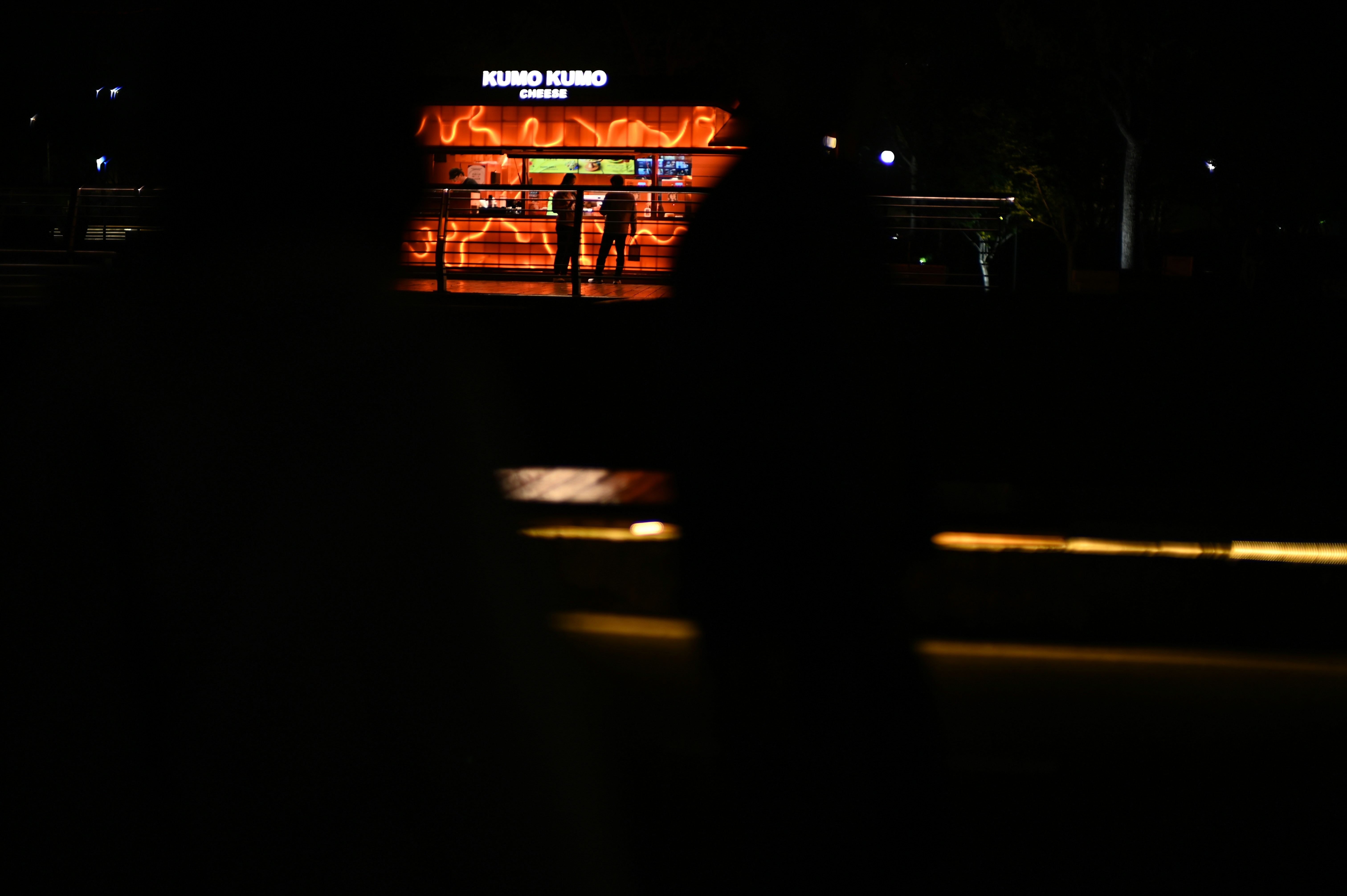 Neon Ember at Night: Silhouettes and a Glowing Kiosk