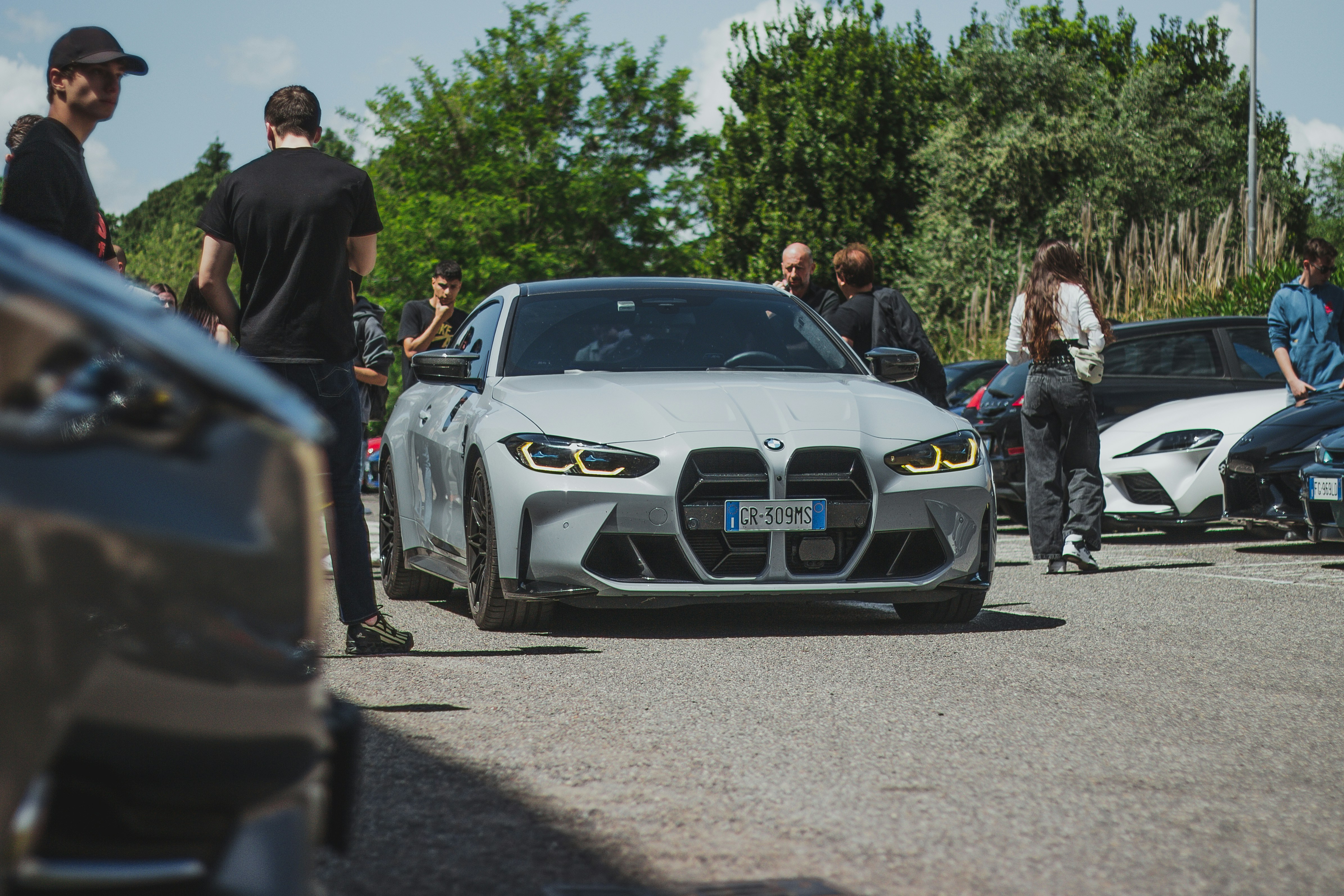 A group of people standing around a white car photo – Free Bmw m4 Image ...