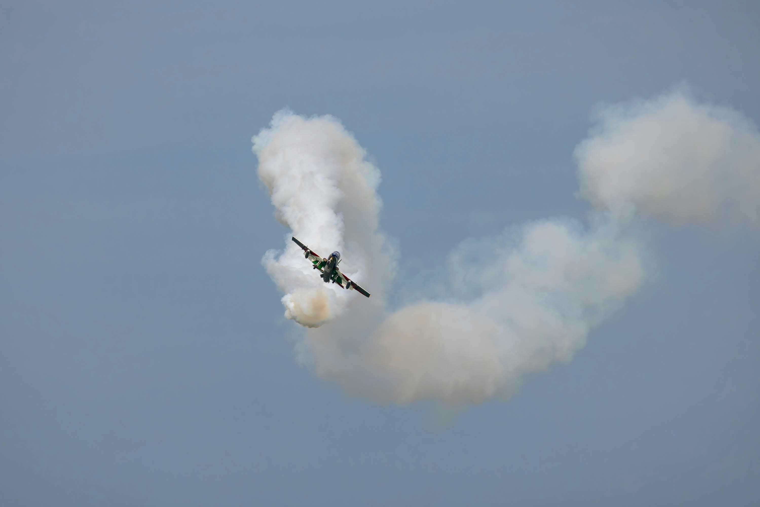 Foto Una avioneta volando por el aire con humo saliendo de él – Imagen ...