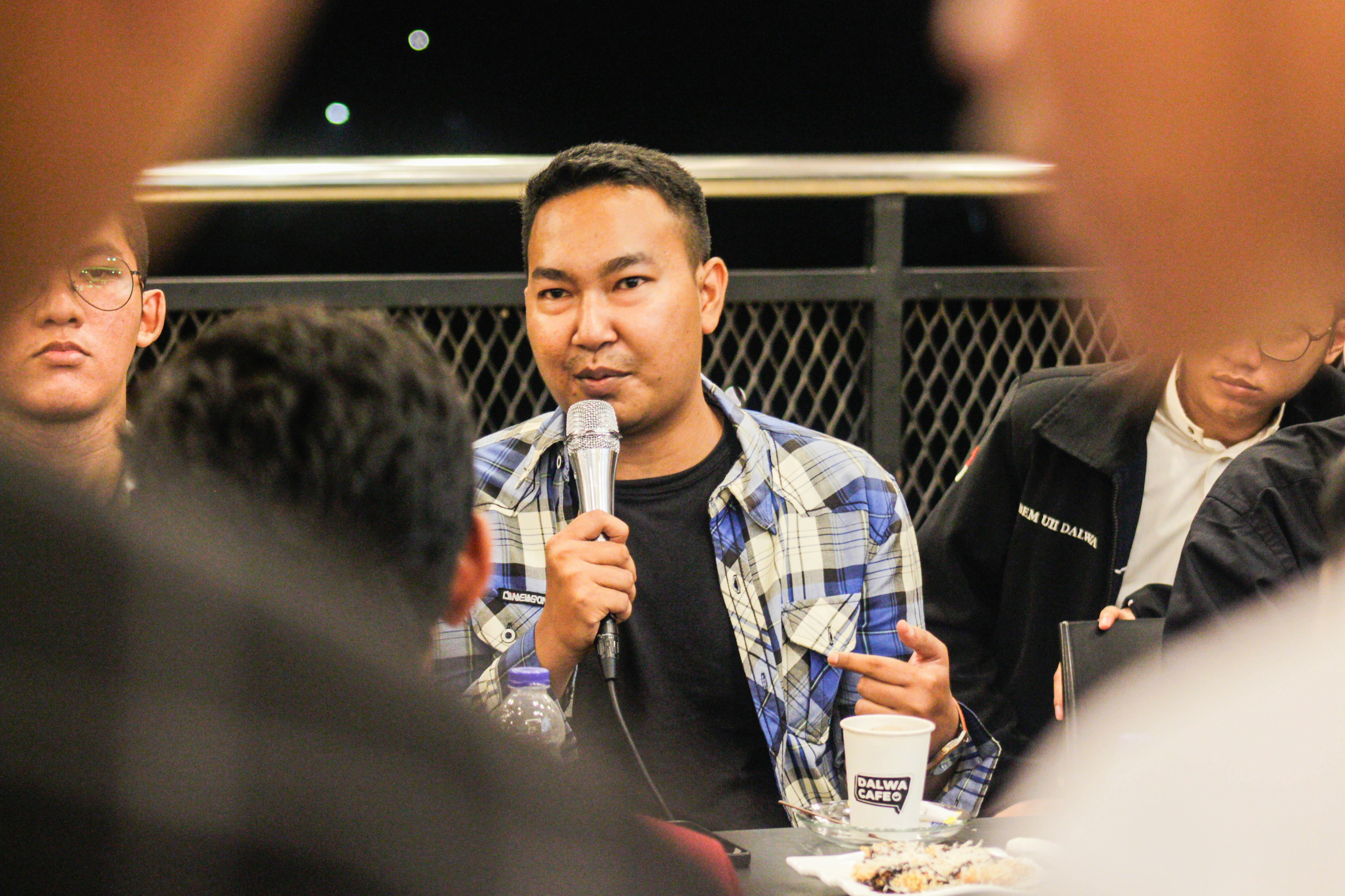 A man holding a microphone in front of a group of people photo – Free ...