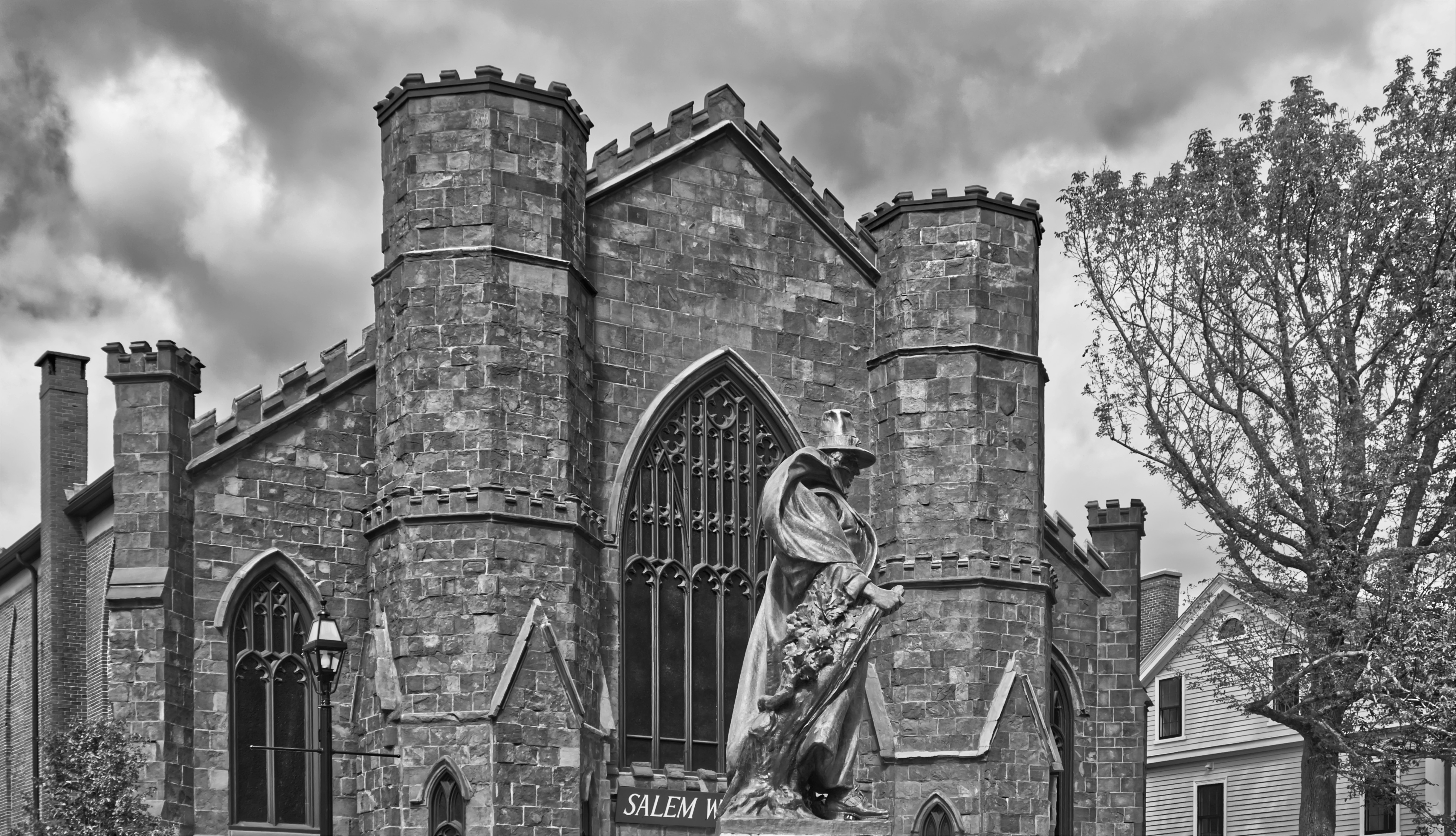 Black and white photo of a historic stone building with gothic architecture under a dramatic sky.