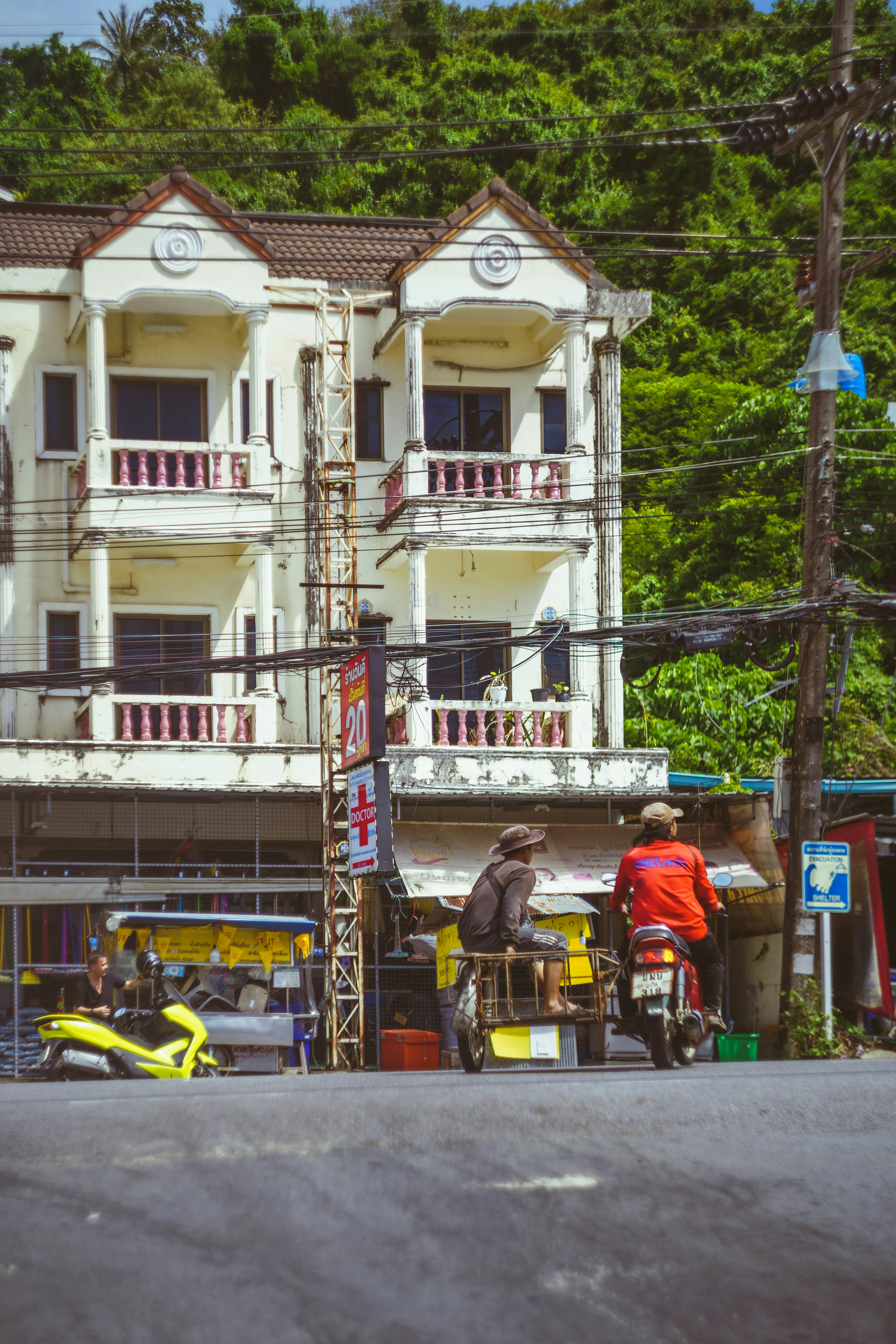 Riders at the Edge: A Street Scene Framed by Worn Balconies and a Tangle of Wires
