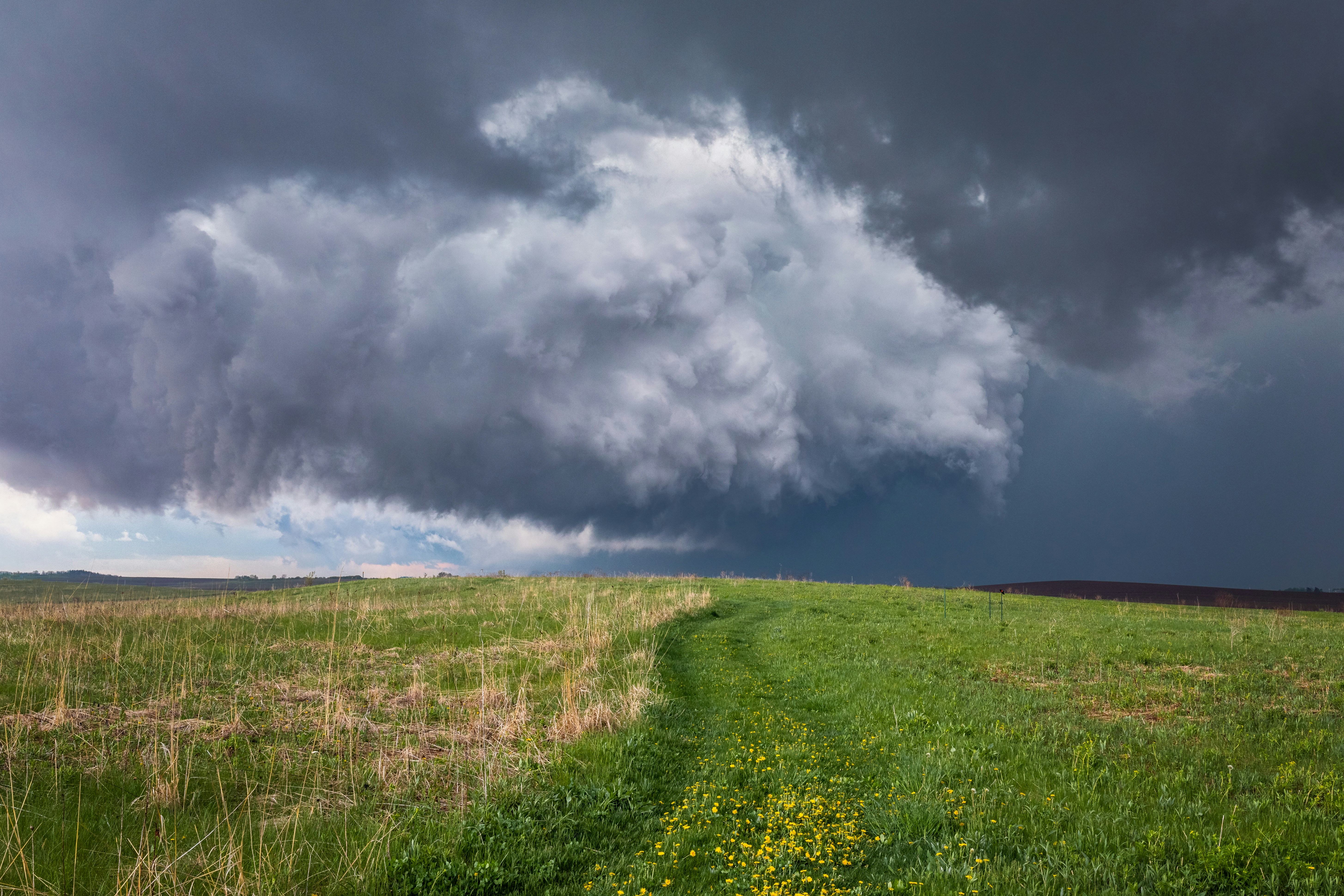 A field with a dirt path leading to a storm cloud photo – Free ...
