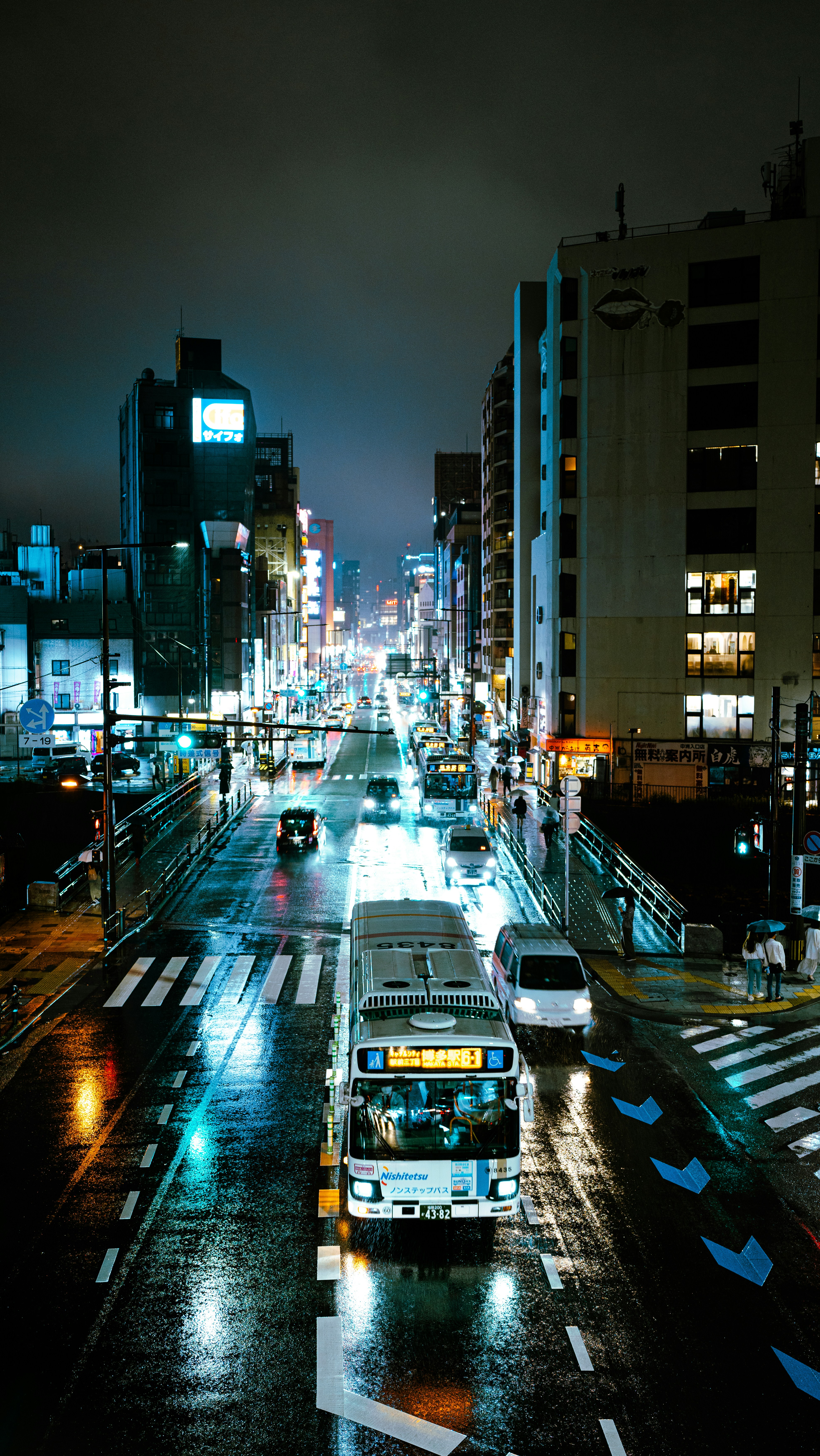 A bustling city intersection at night, illuminated by vibrant neon lights and rain-soaked streets, showcasing the dynamic flow of urban life.