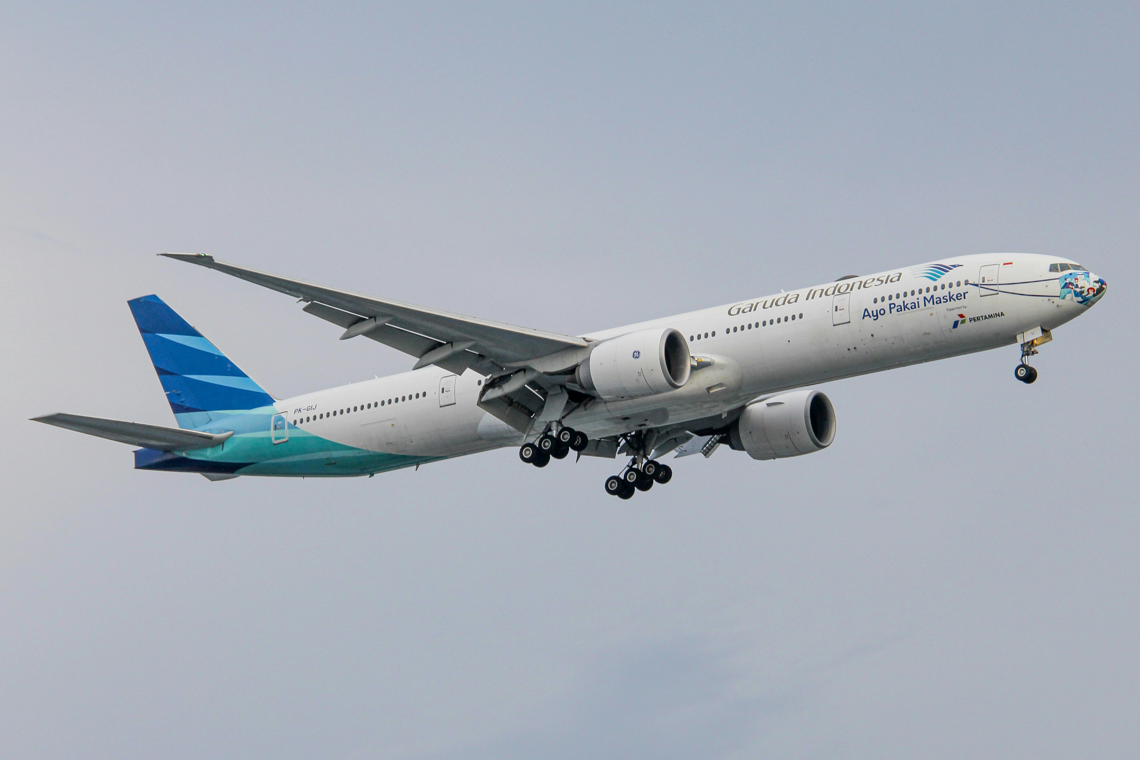 A large passenger jet flying through a gray sky photo – Free Jakarta ...