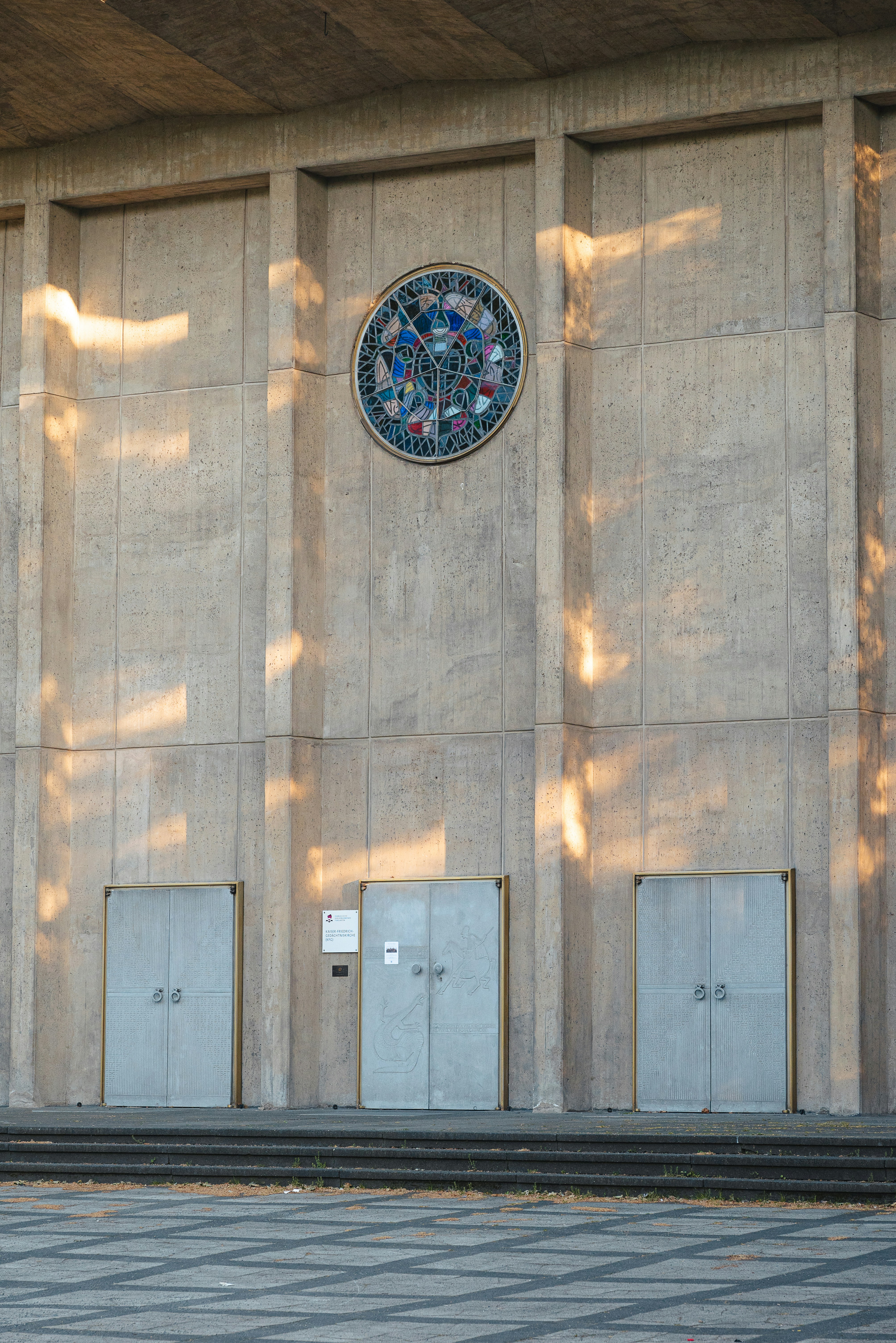 Circular Mosaic Window Anchoring a Quiet Concrete Facade