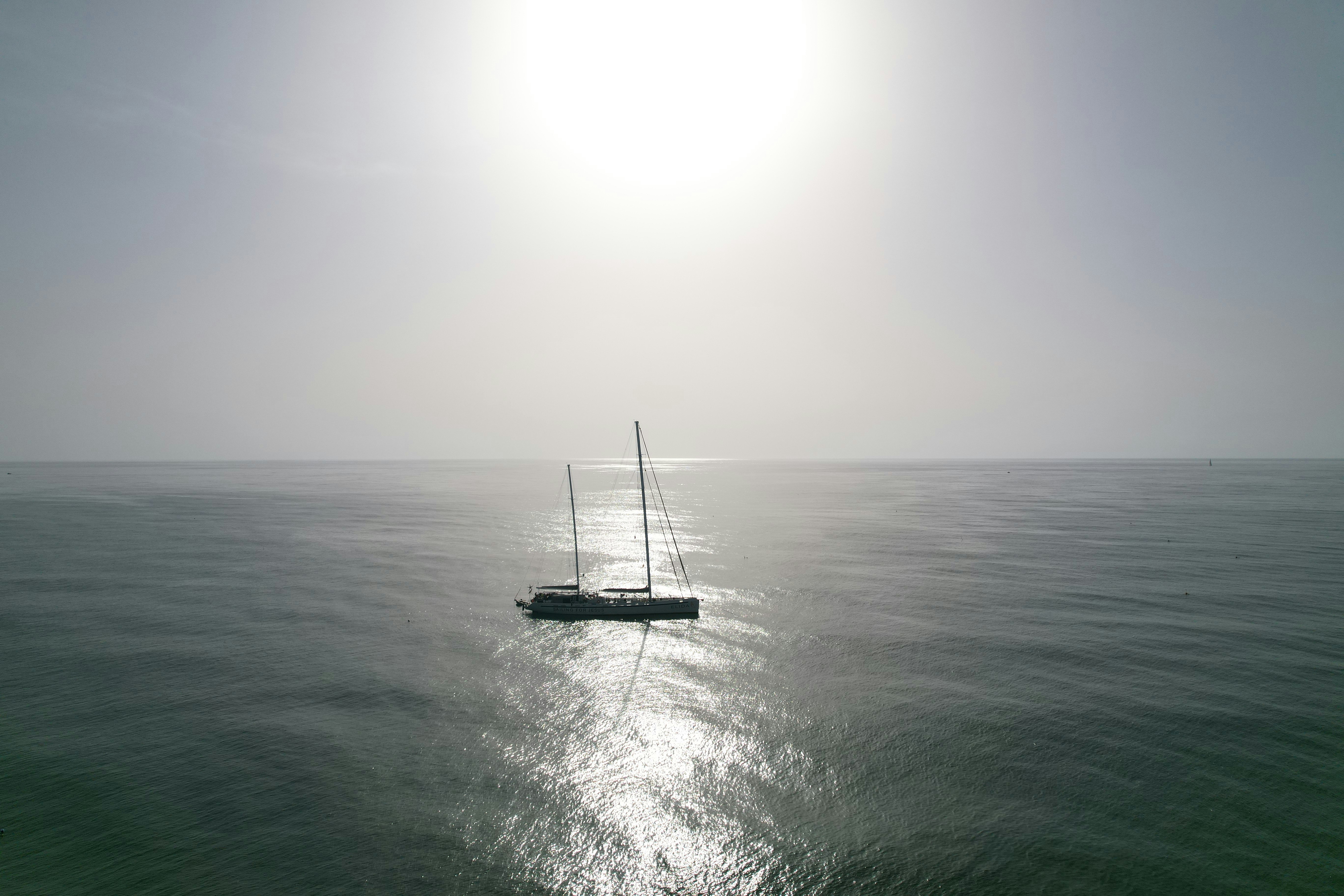 A sailboat floating in the middle of the ocean photo – Free Boat Image ...