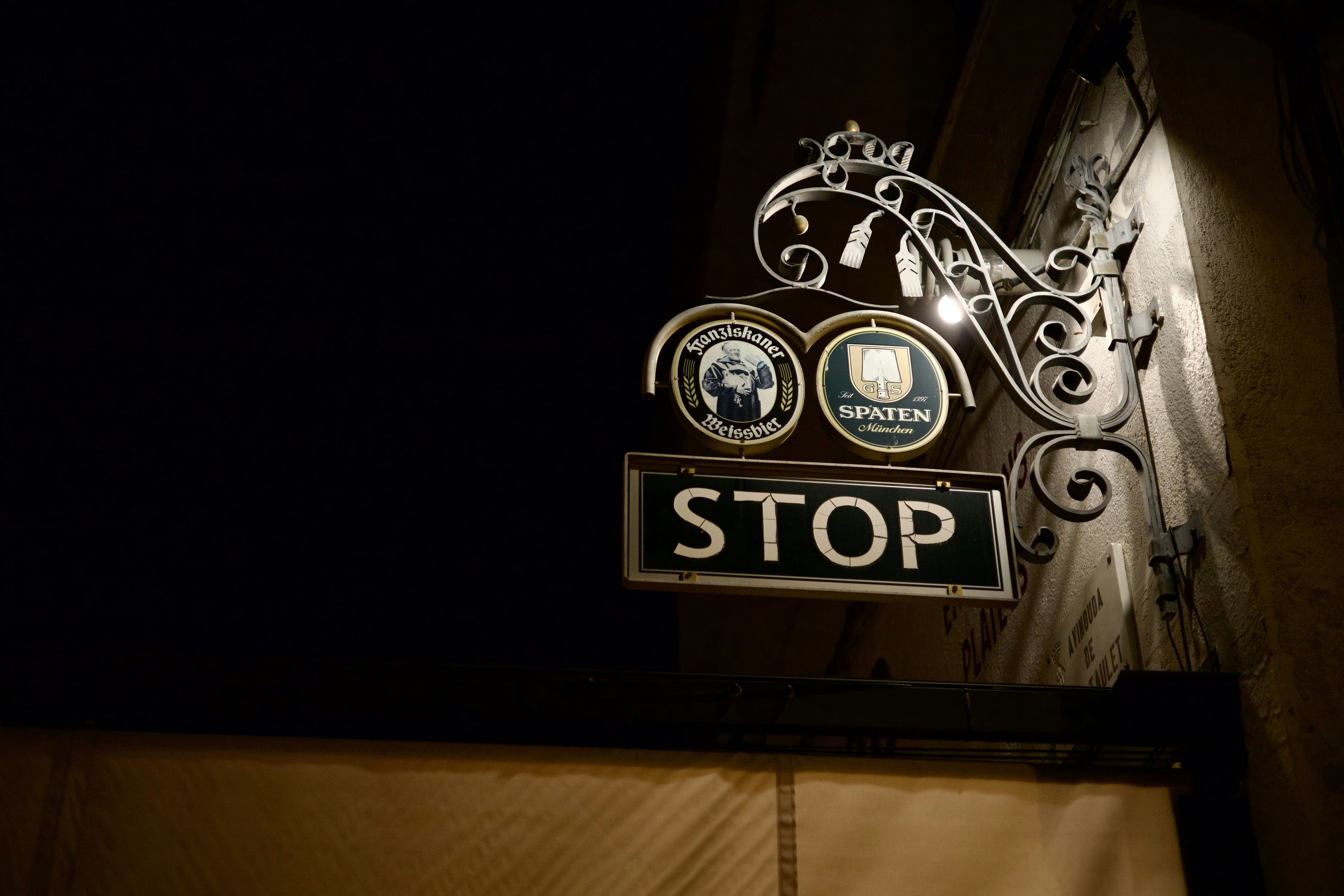 Ornate Night Stop Sign: Warm Glow Beneath Iron Crest