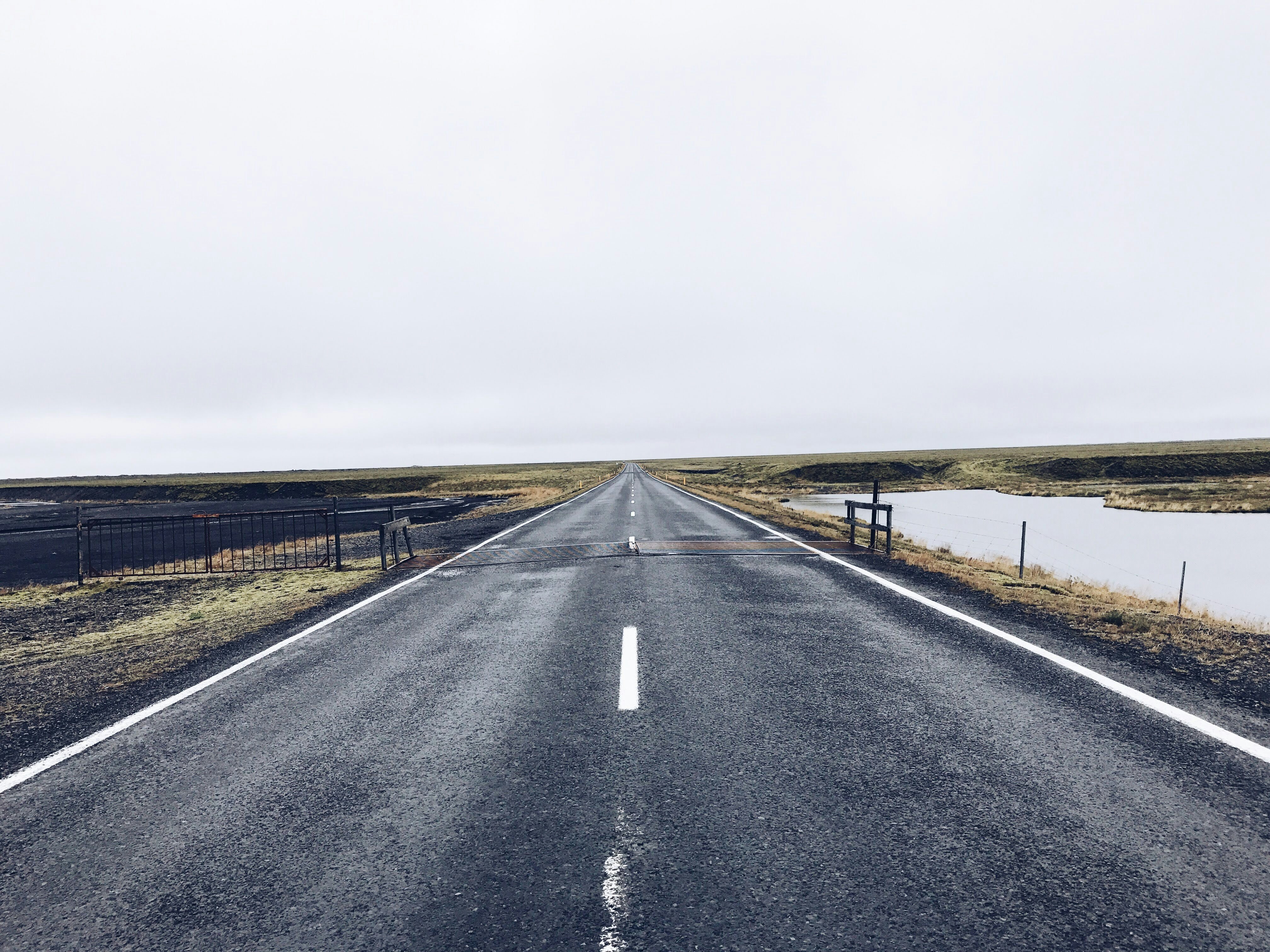 An empty road with a puddle of water in the middle of it photo – Free ...