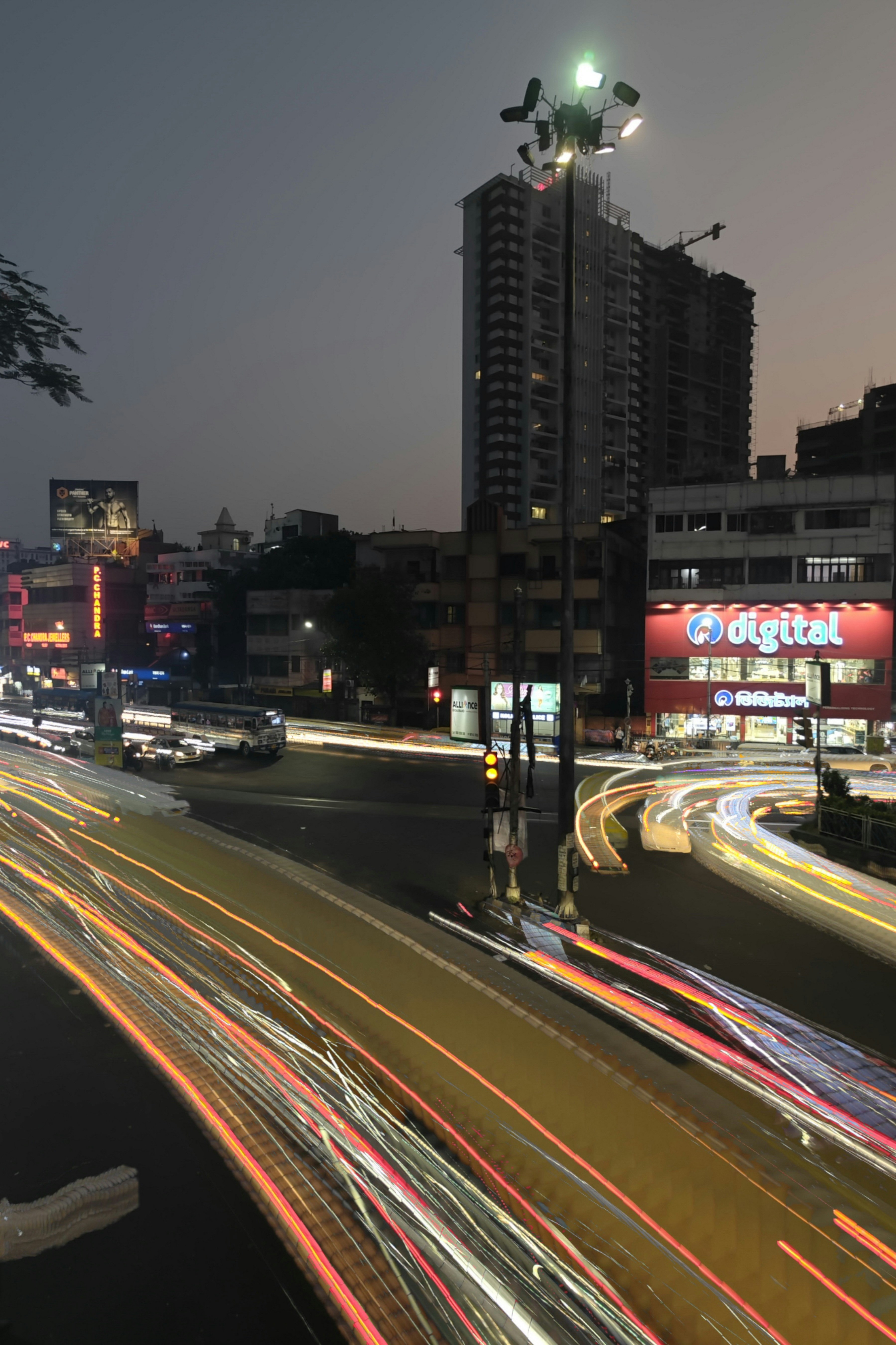 Dynamic light trails from vehicles weave through a bustling city intersection at dusk, showcasing the vibrant energy of urban life.