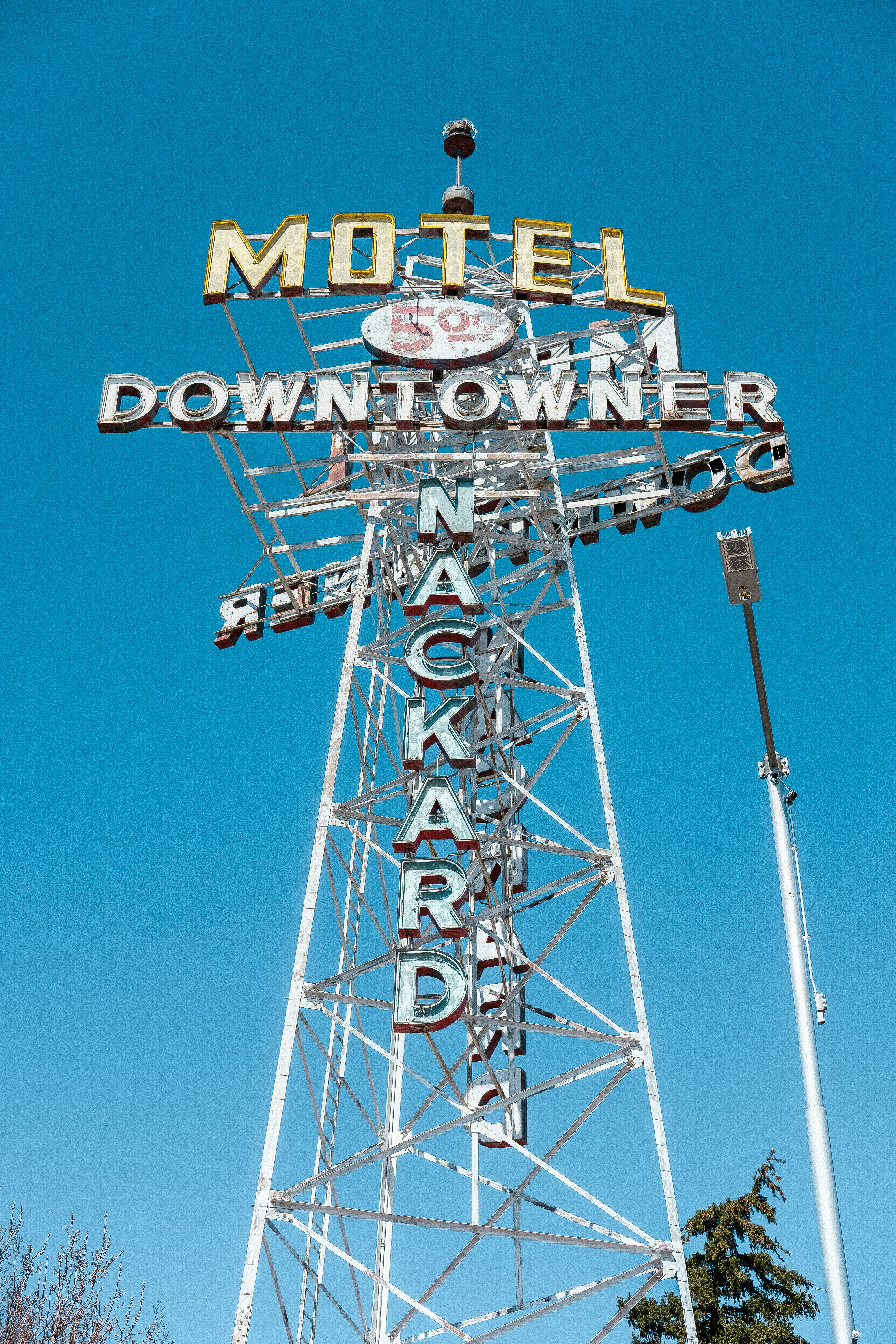 Vintage motel signage towering against a clear blue sky, showcasing retro typography and vibrant colors.