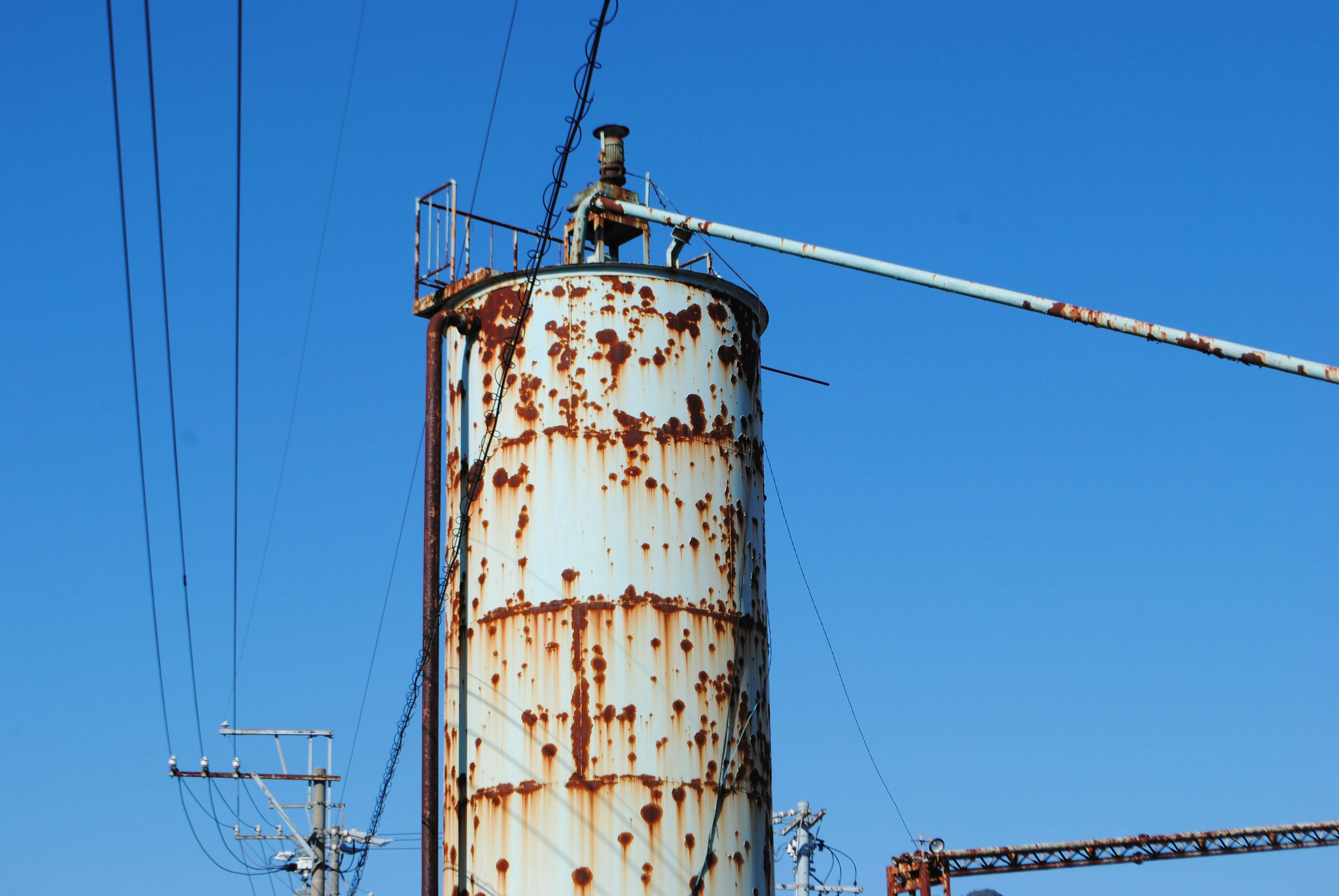A rusted metal tower with power lines in the background photo – Free ...