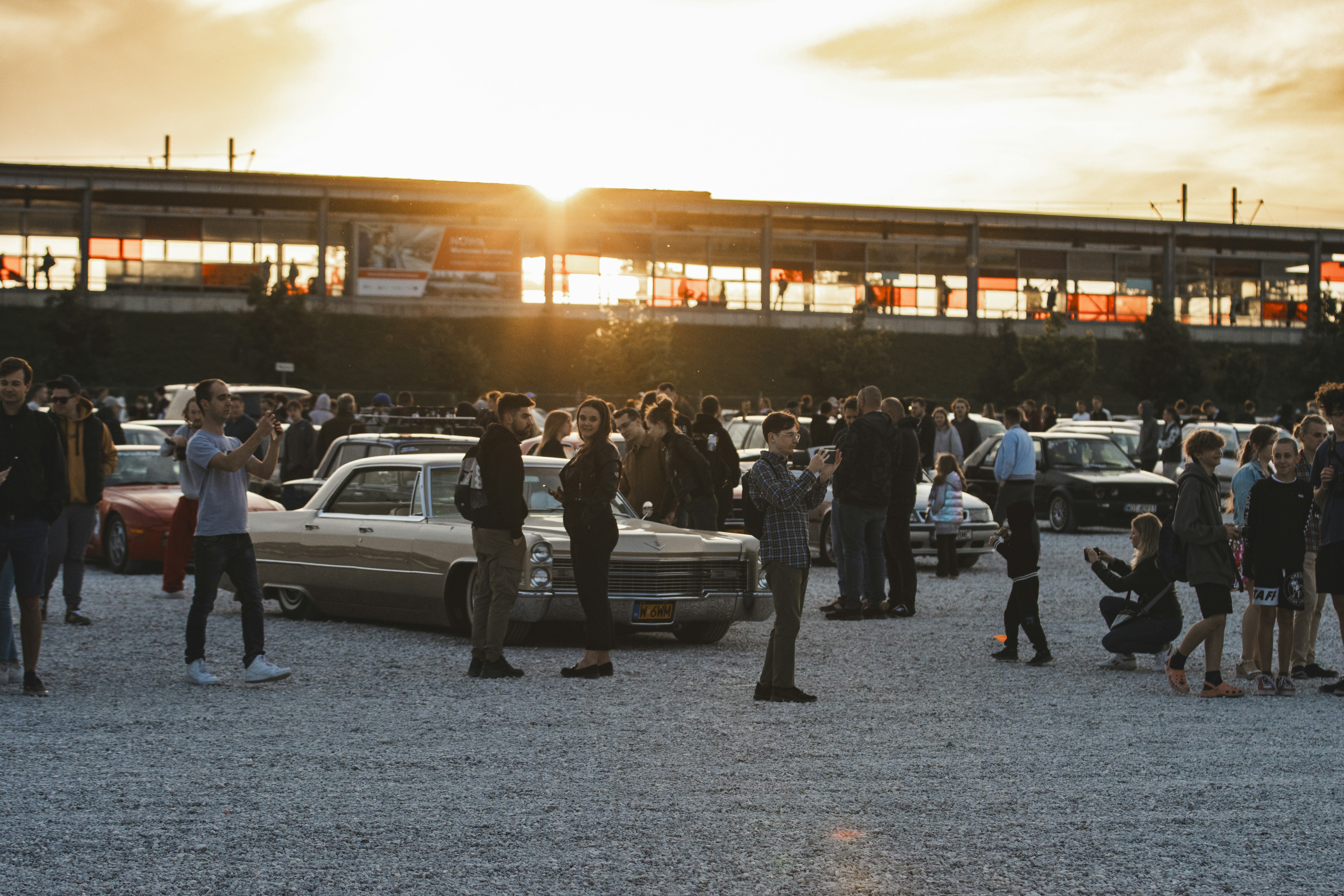 Sunset Gala by the Lot: People, Cars, and a Glowing Horizon