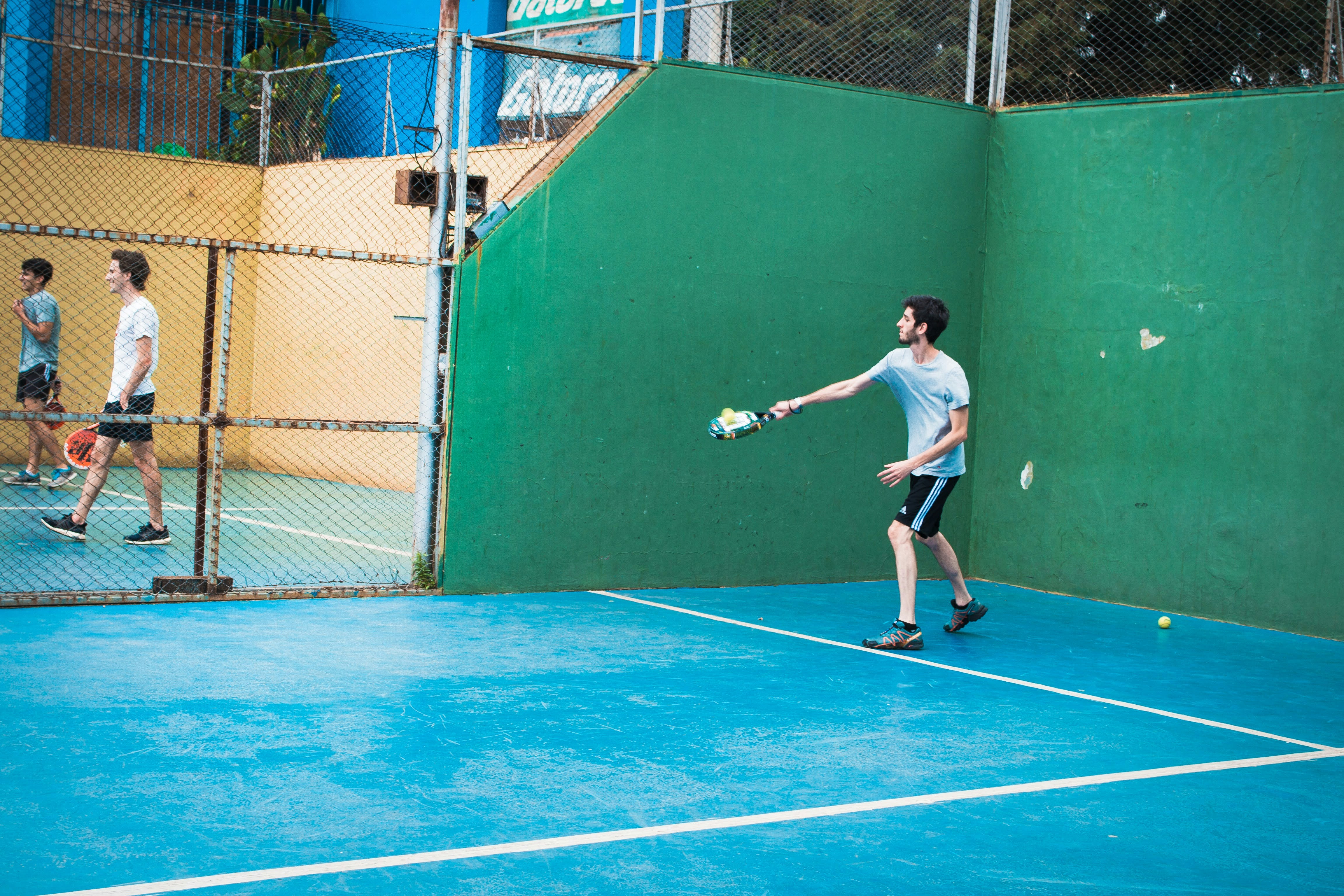 A man holding a tennis racquet on top of a tennis court photo – Free ...
