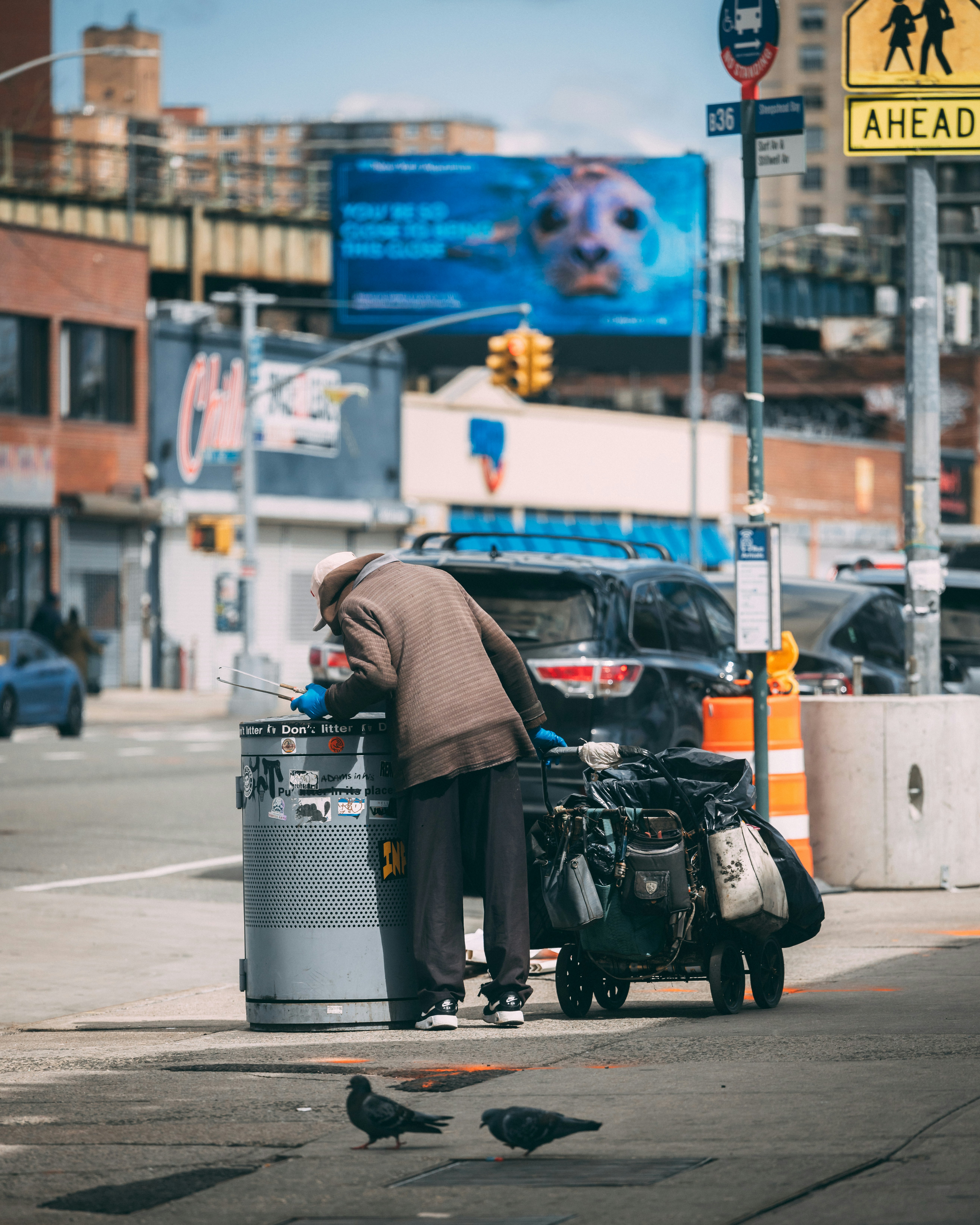 A person leaning over a trash can on a city street photo – Free Coney ...
