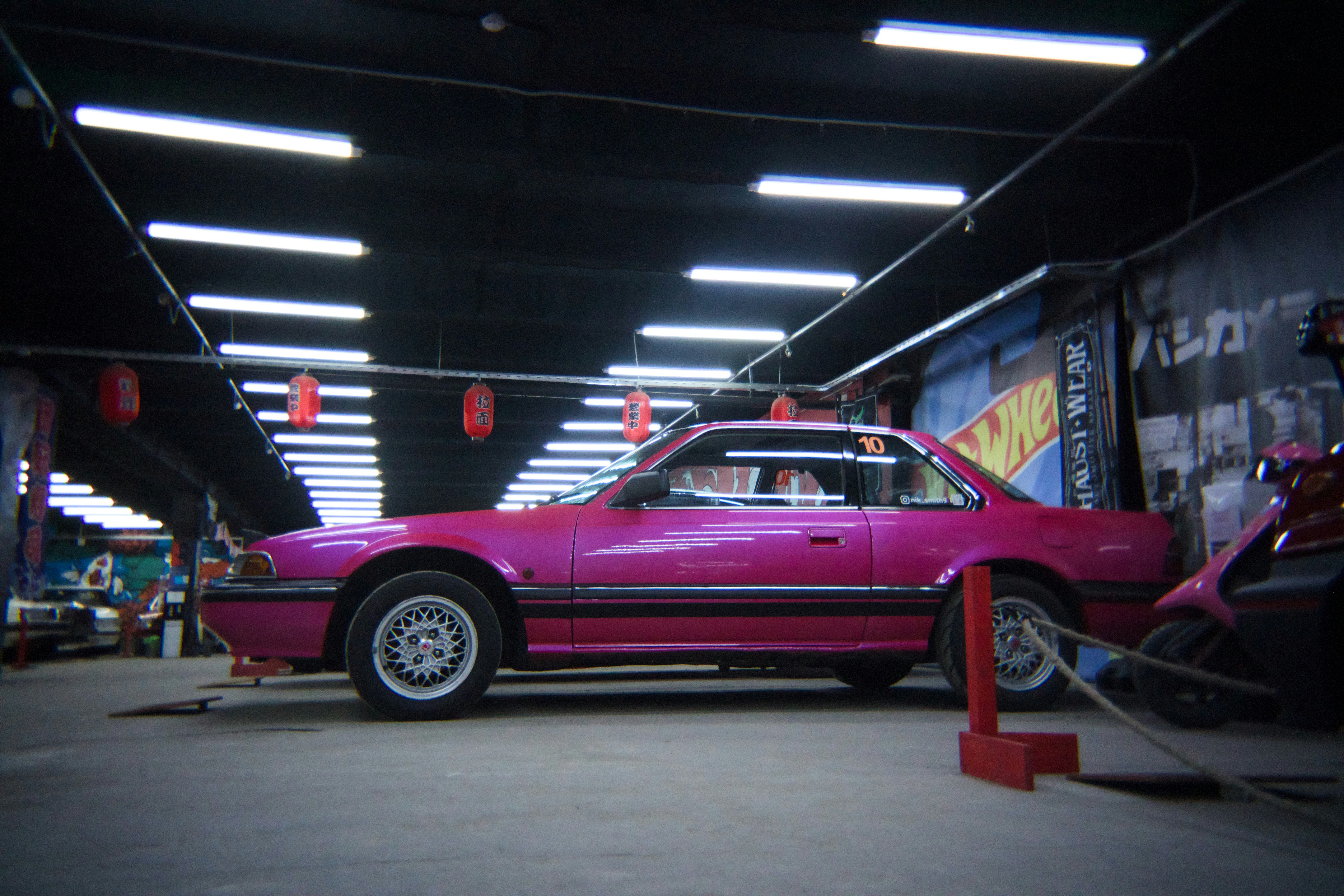 Neon Showroom Classic: A Pink Vintage Coupe Under Industrial Fluorescence