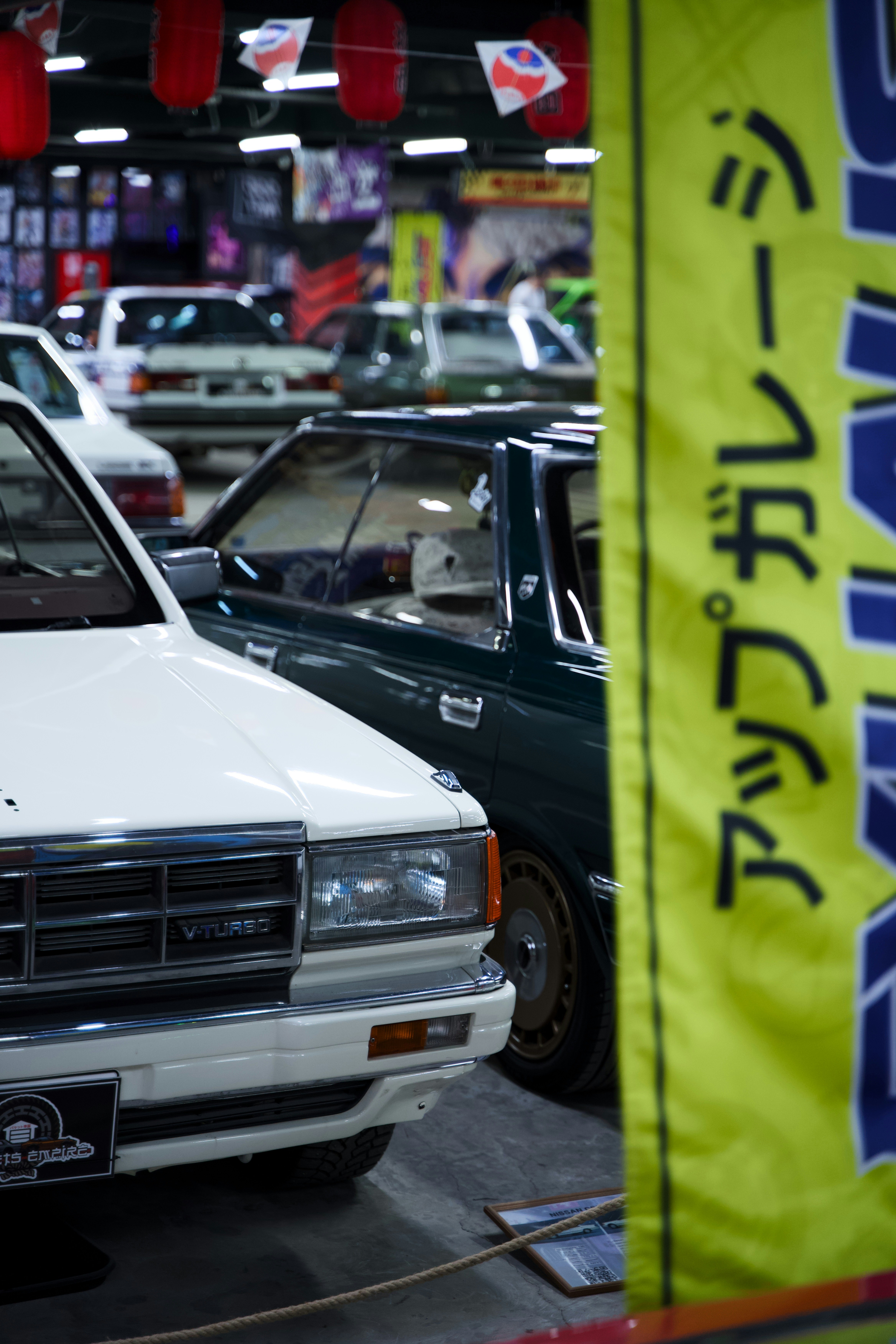 Front-Row at a Classic Car Show: White Pickup Framed by a Neon Banner